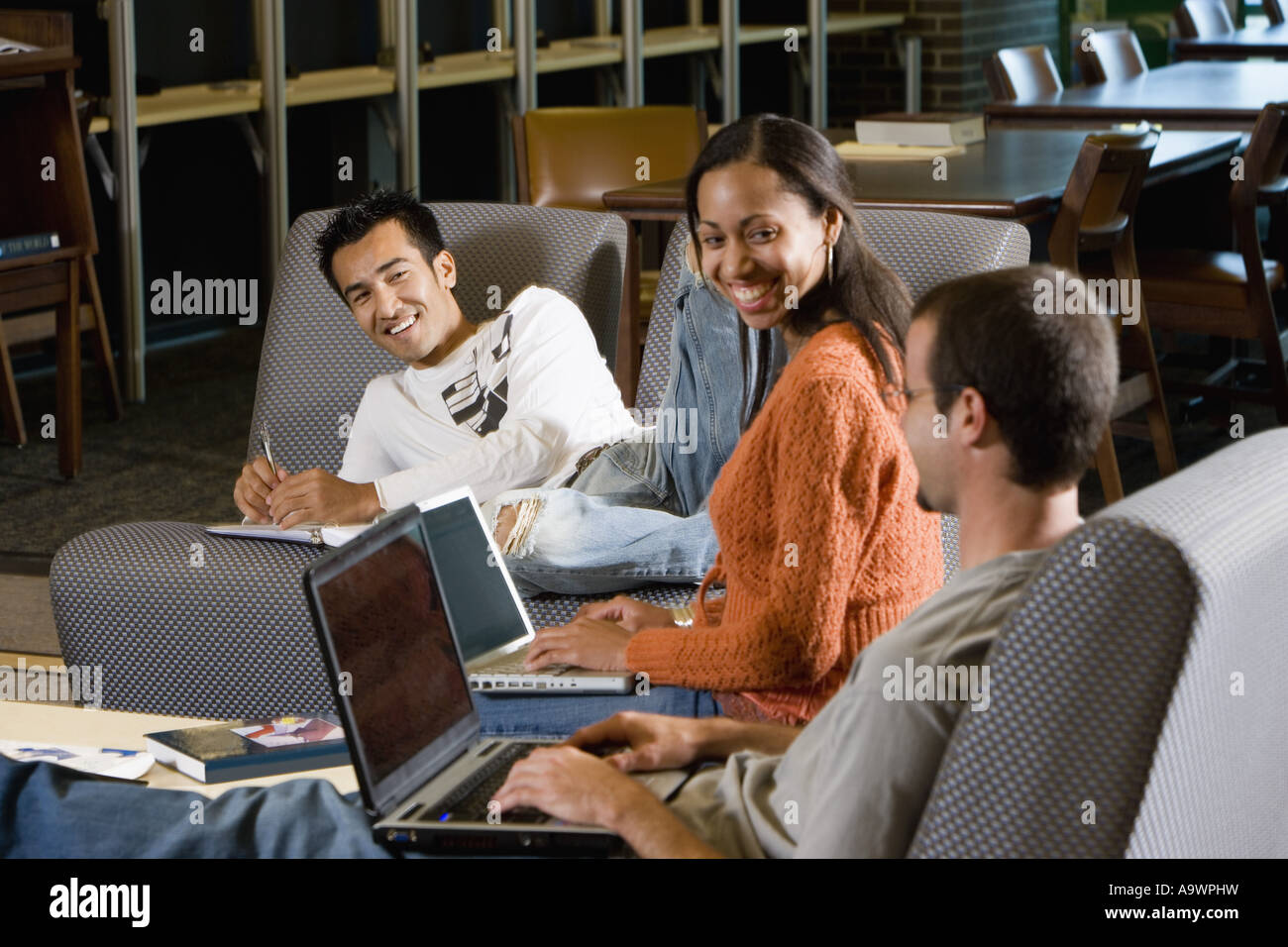 Students with laptop computers in library sitting on sofas studying ...
