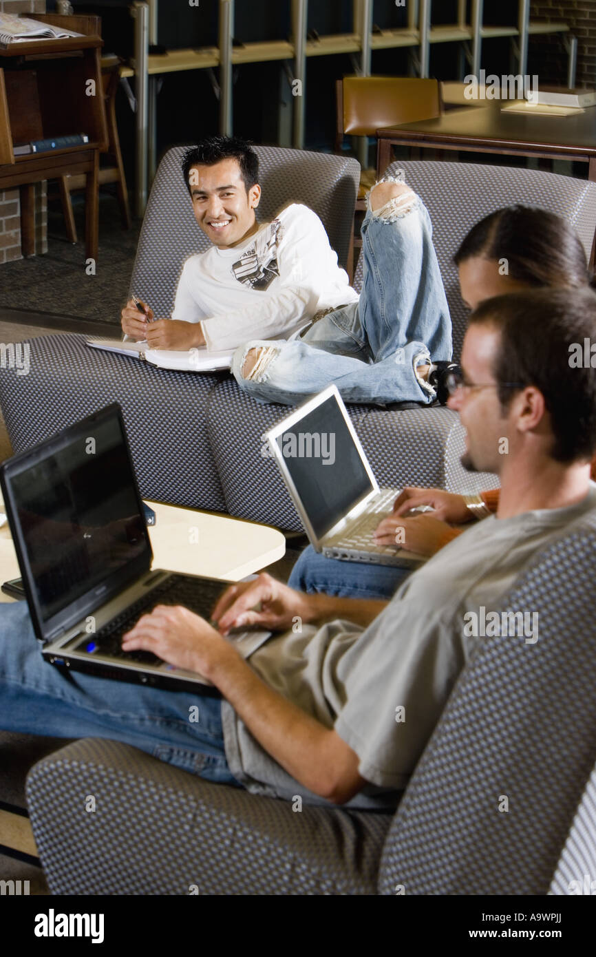 Students with laptop computers in library sitting on sofas studying ...
