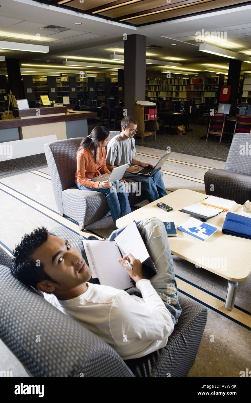 Students with laptop computers in library sitting on sofas studying ...