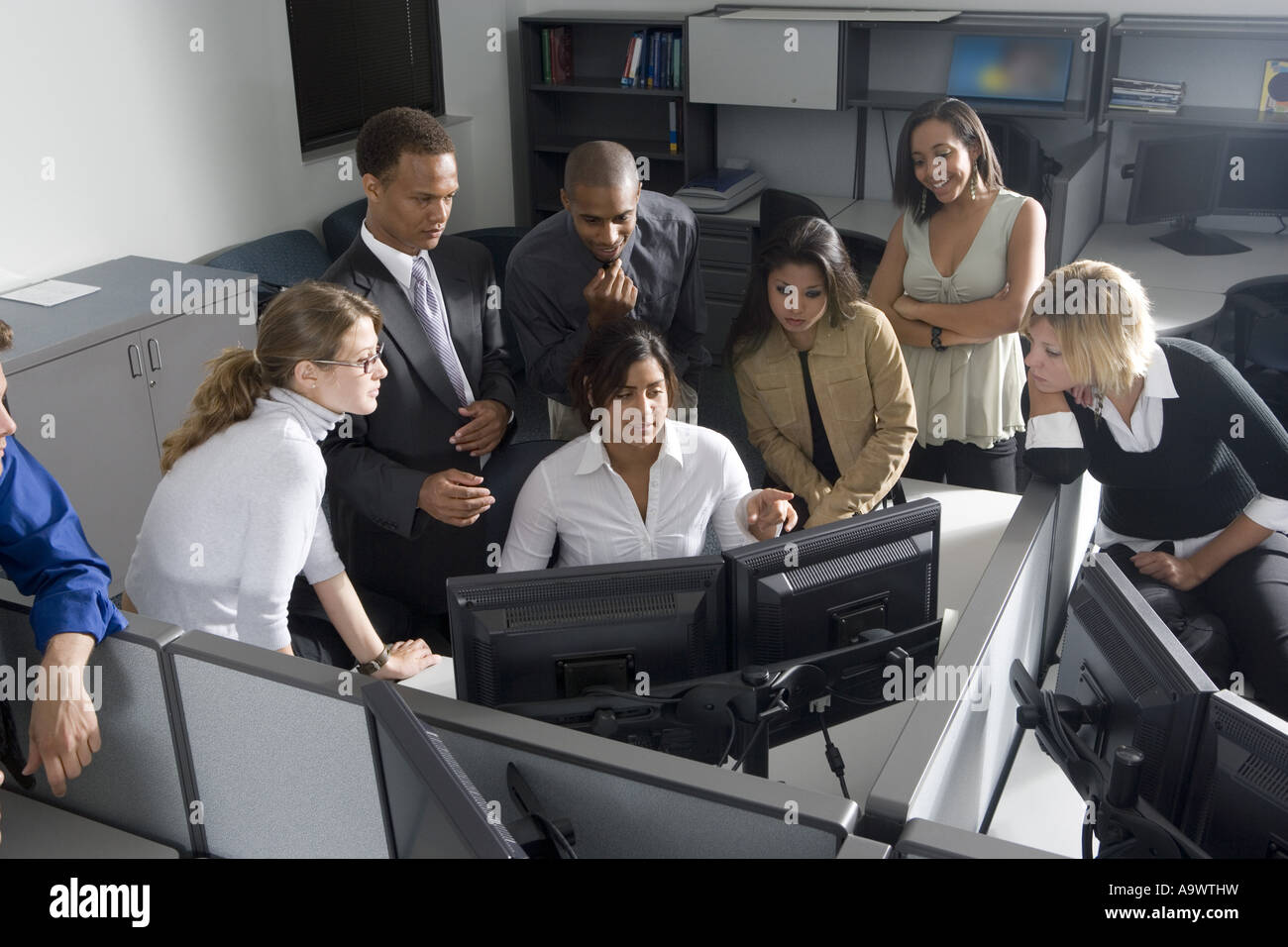Group of young workers in office gathered around computer screen Stock ...