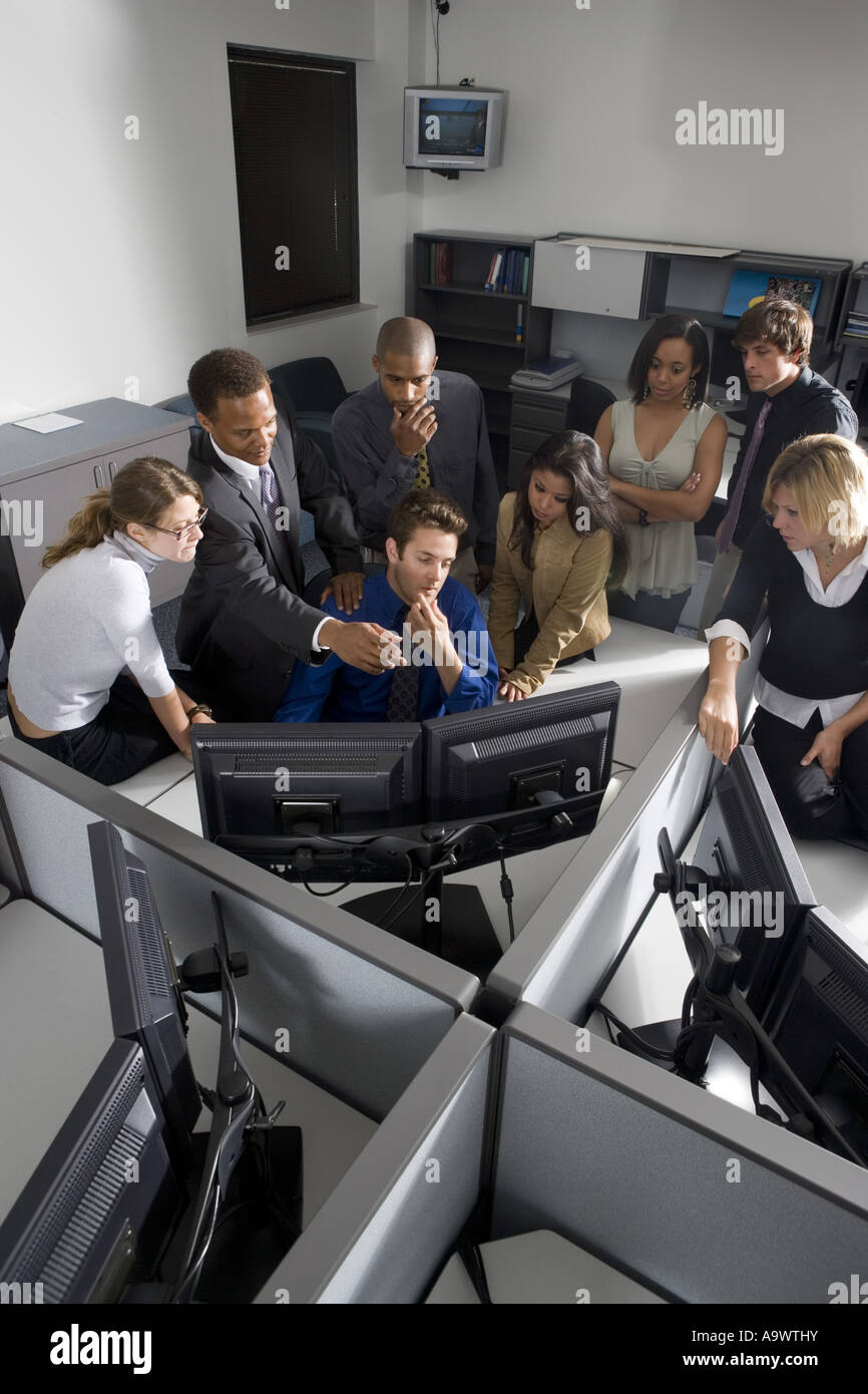 Group of young workers in office gathered around computer screen Stock ...