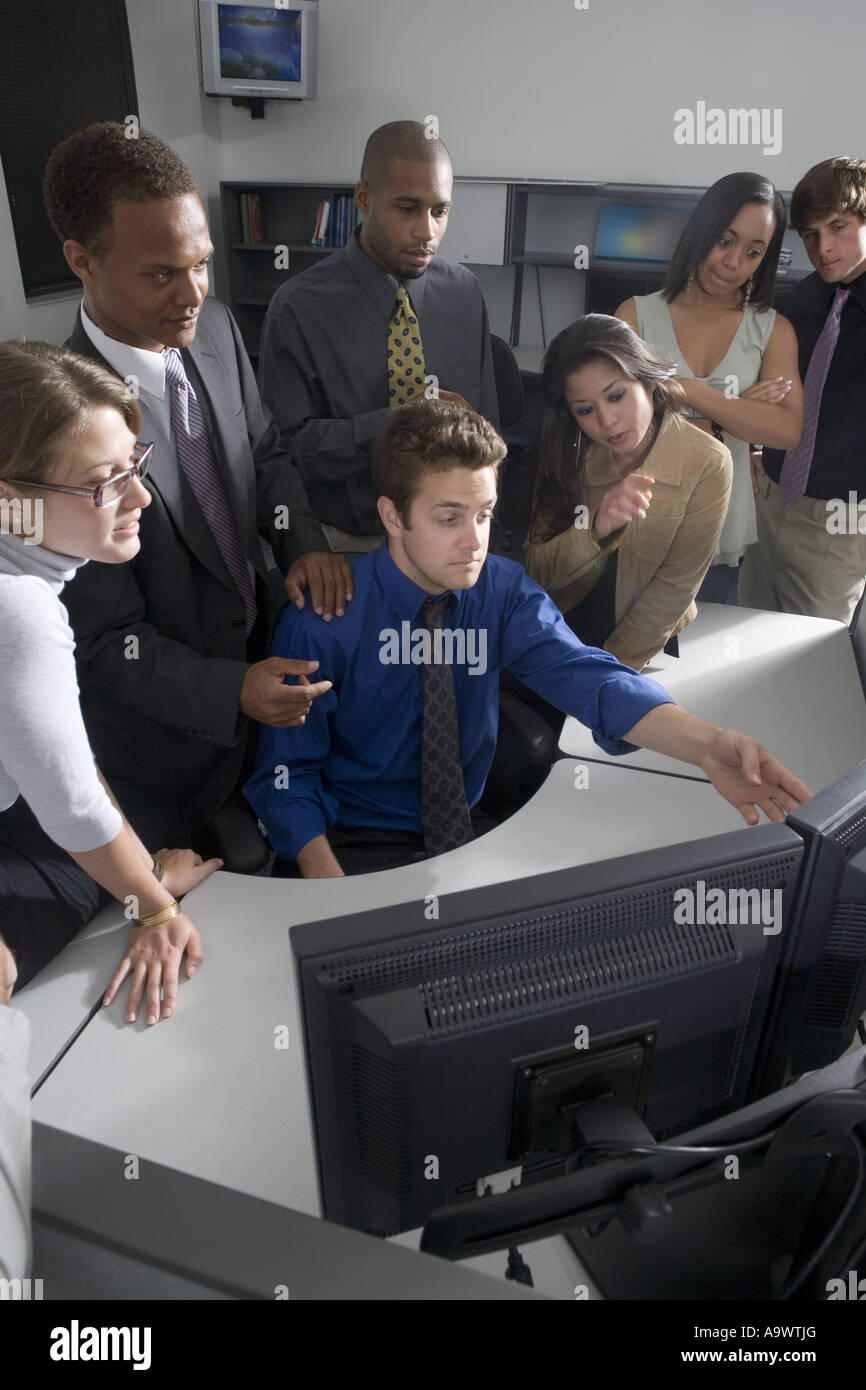Group of young workers in office gathered around computer screen Stock ...