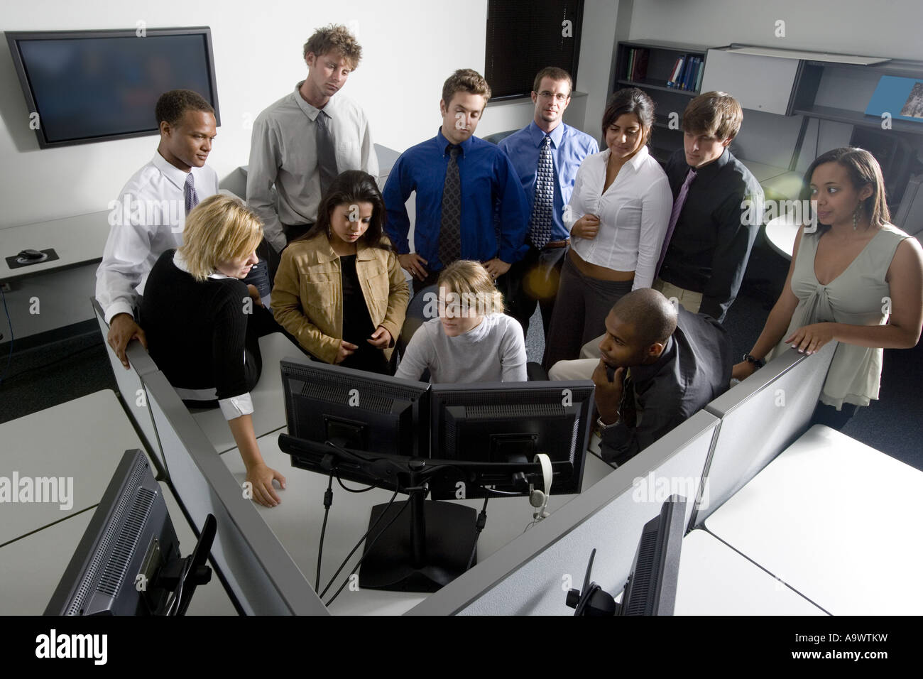 Group of young workers in office gathered around computer screen Stock ...
