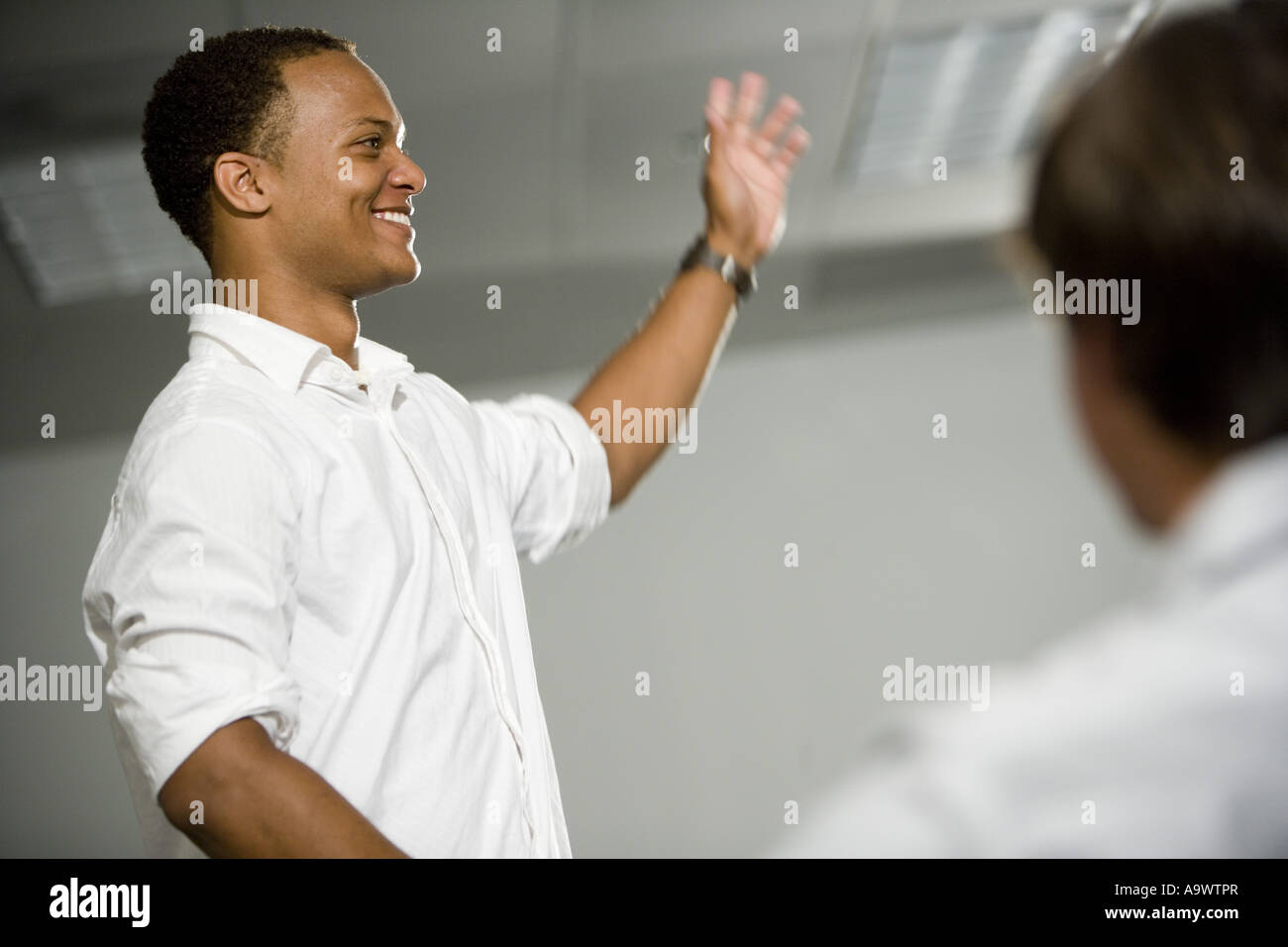 Teacher standing in the classroom gesturing towards class Stock Photo ...
