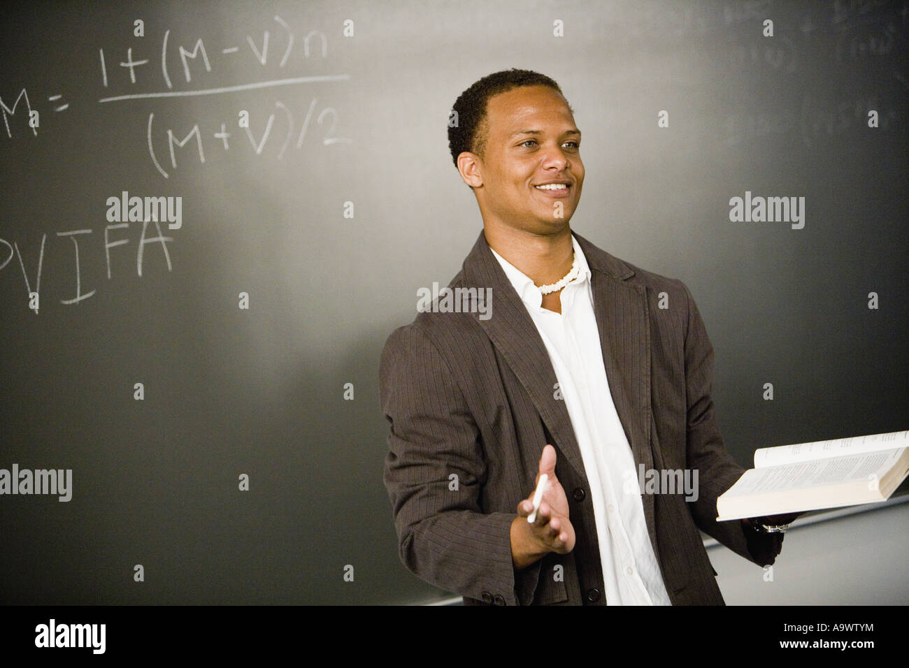 Teacher in front of chalk board teaching in the classroom Stock Photo ...