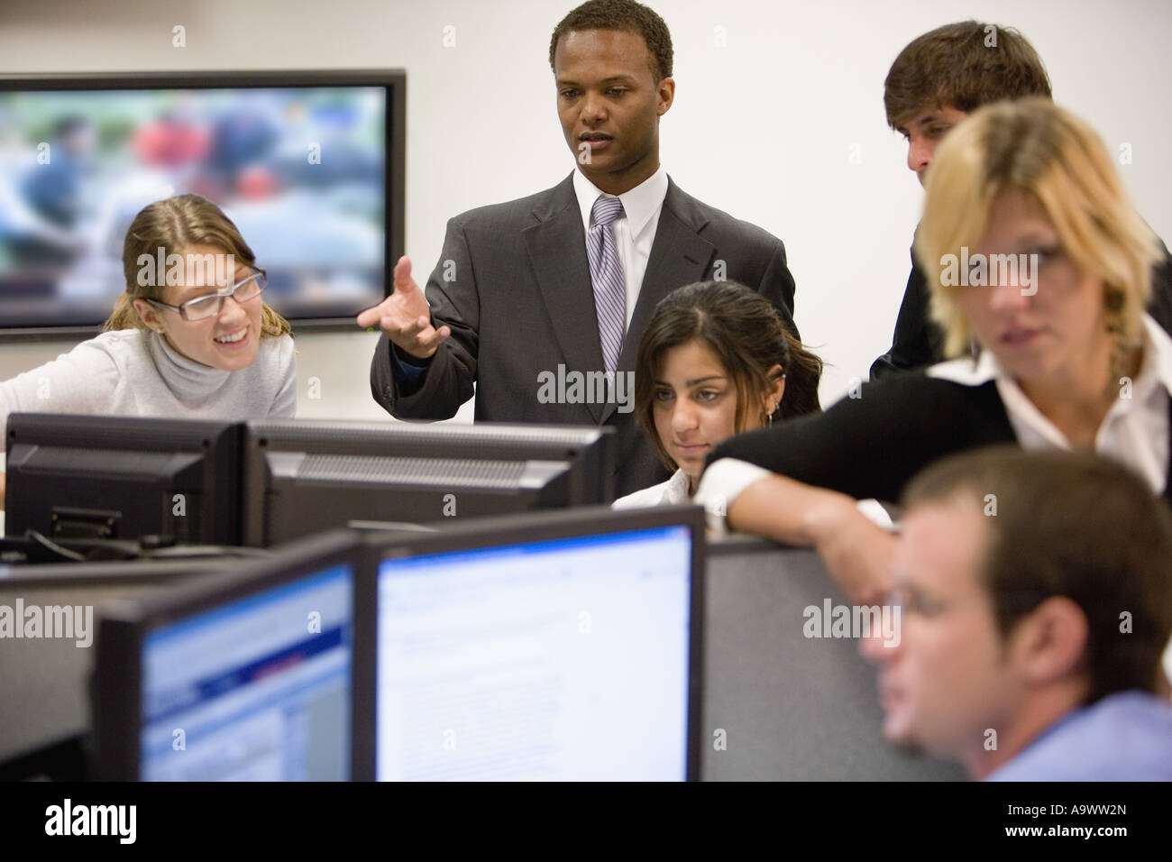 Office workers gathered around computer screens Stock Photo - Alamy