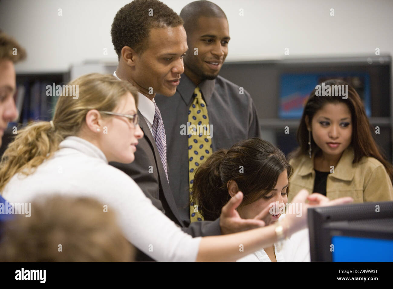 Close-up of office workers gathered around computer Stock Photo - Alamy