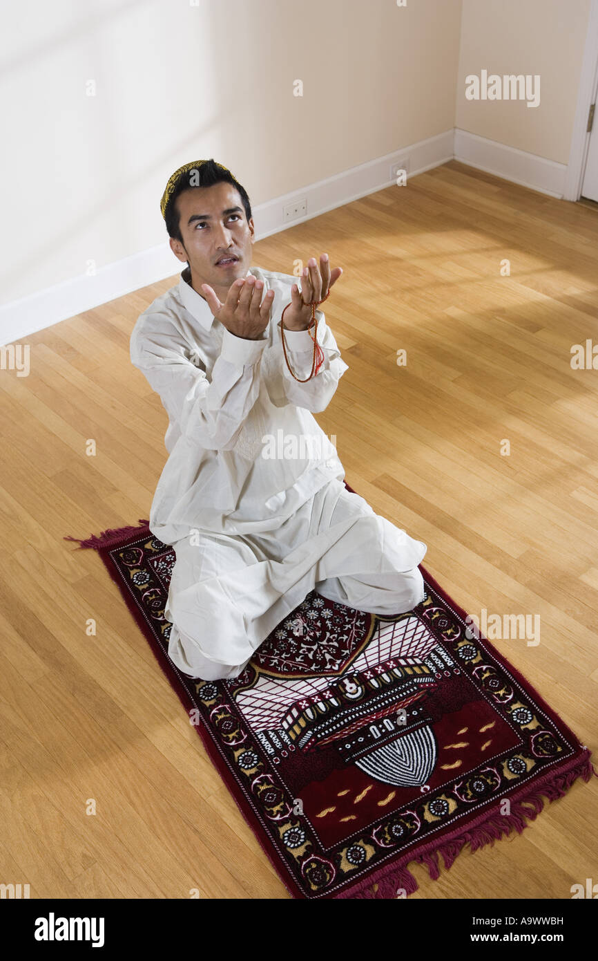 A Muslim man praying on a prayer mat Stock Photo - Alamy