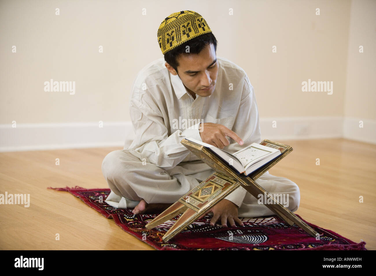 A Muslim man reading Koran on a prayer mat Stock Photo - Alamy