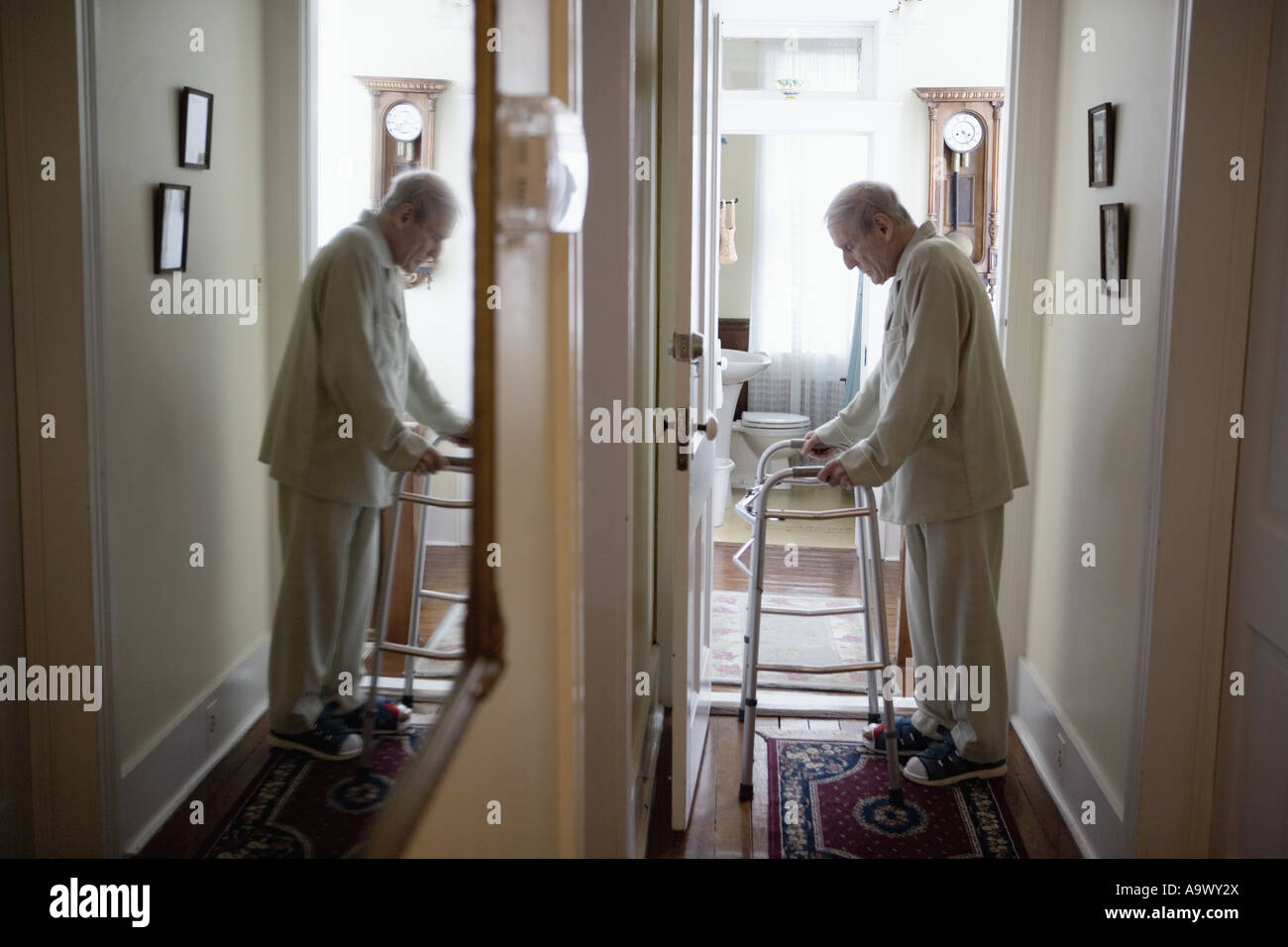 Feeble senior man slowly going down hallway with walker Stock Photo - Alamy