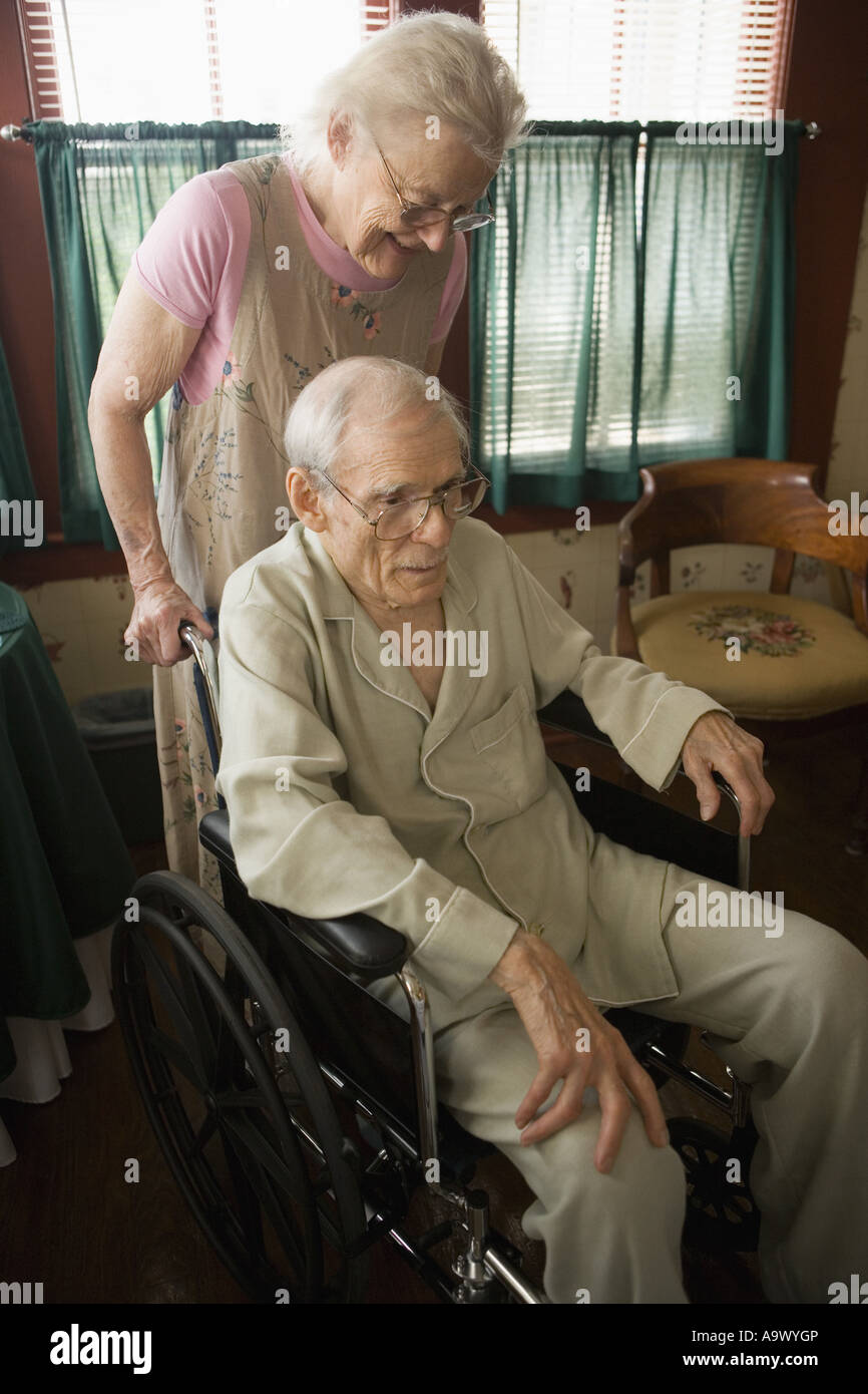Senior woman helping senior man in a wheelchair Stock Photo - Alamy