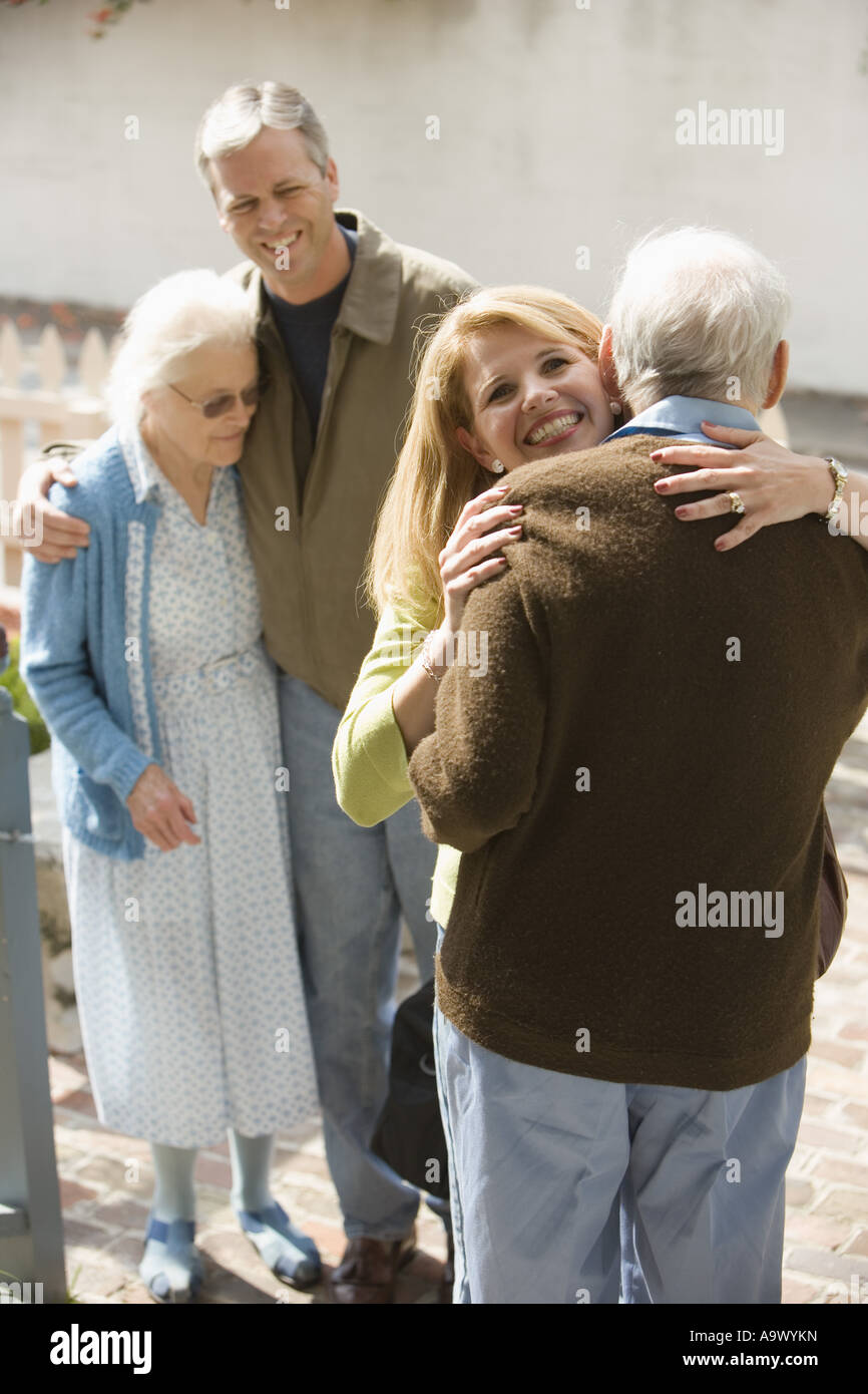 Woman hugging senior man while man and senior woman watch Stock Photo ...
