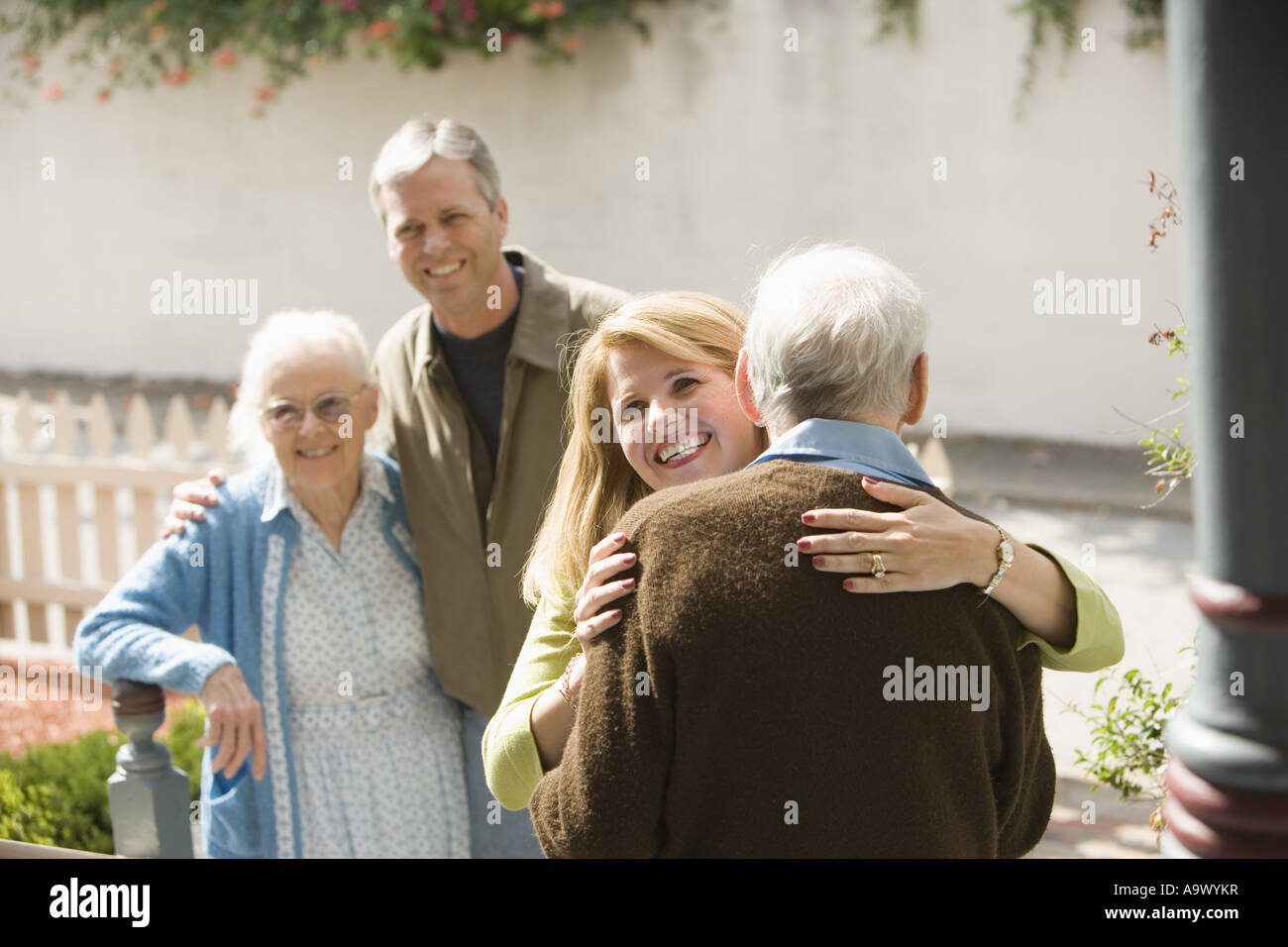 Woman hugging senior man while man and senior woman watch Stock Photo ...