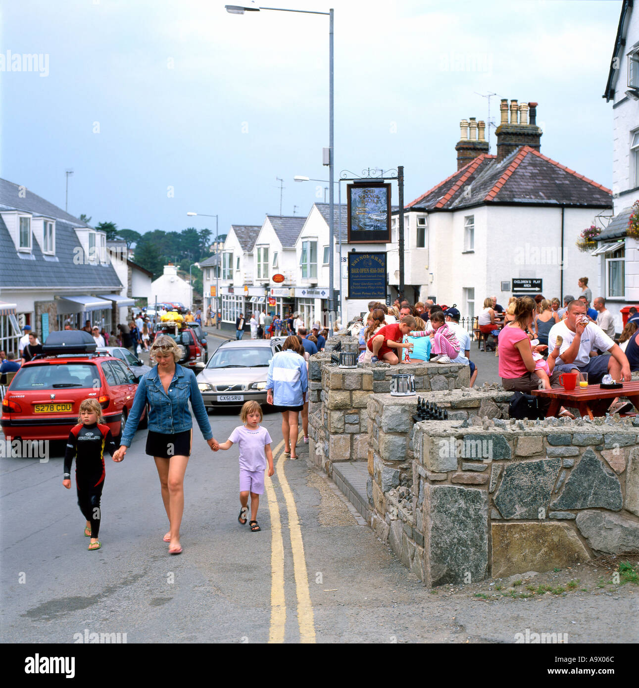 Mother and girls walking along a street in the town of Abersoch on the ...