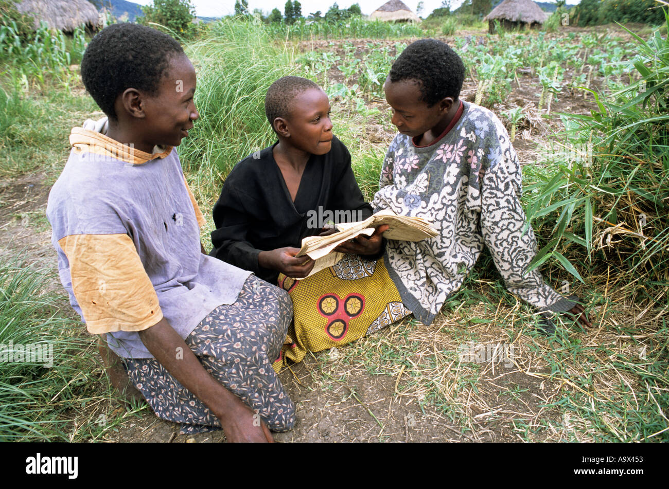 Lolgorian, Kenya. Three girls sitting on the ground reading from a ...