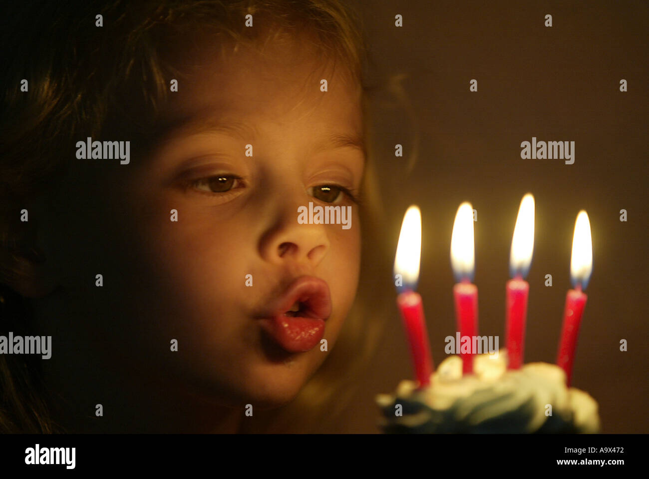 Child blowing out candles at her fourth birthday party Stock Photo - Alamy