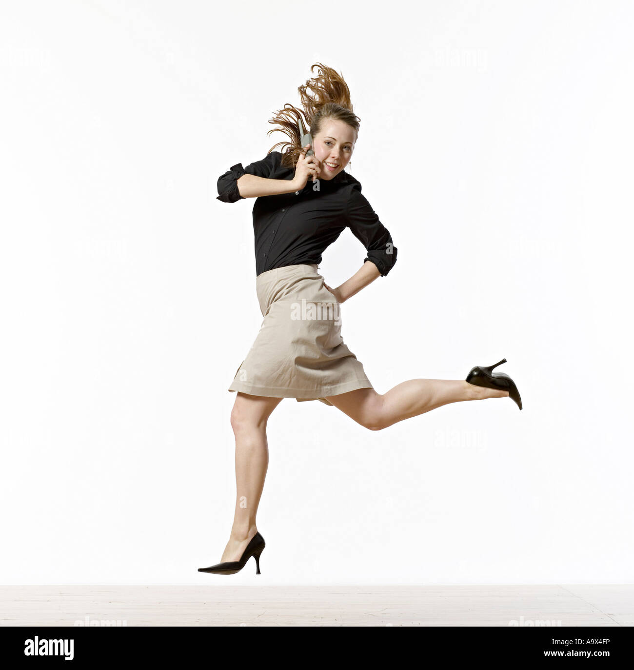 Young attractive woman is running or jumping while talking on a cell ...