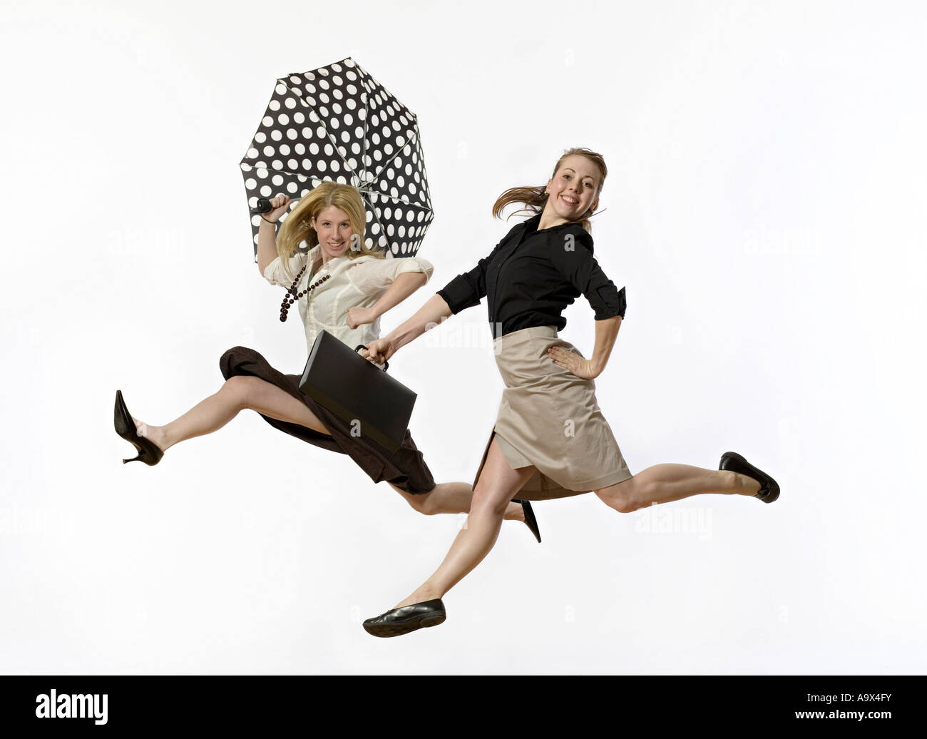 two young women leaping in the air wearing office clothes one with a ...
