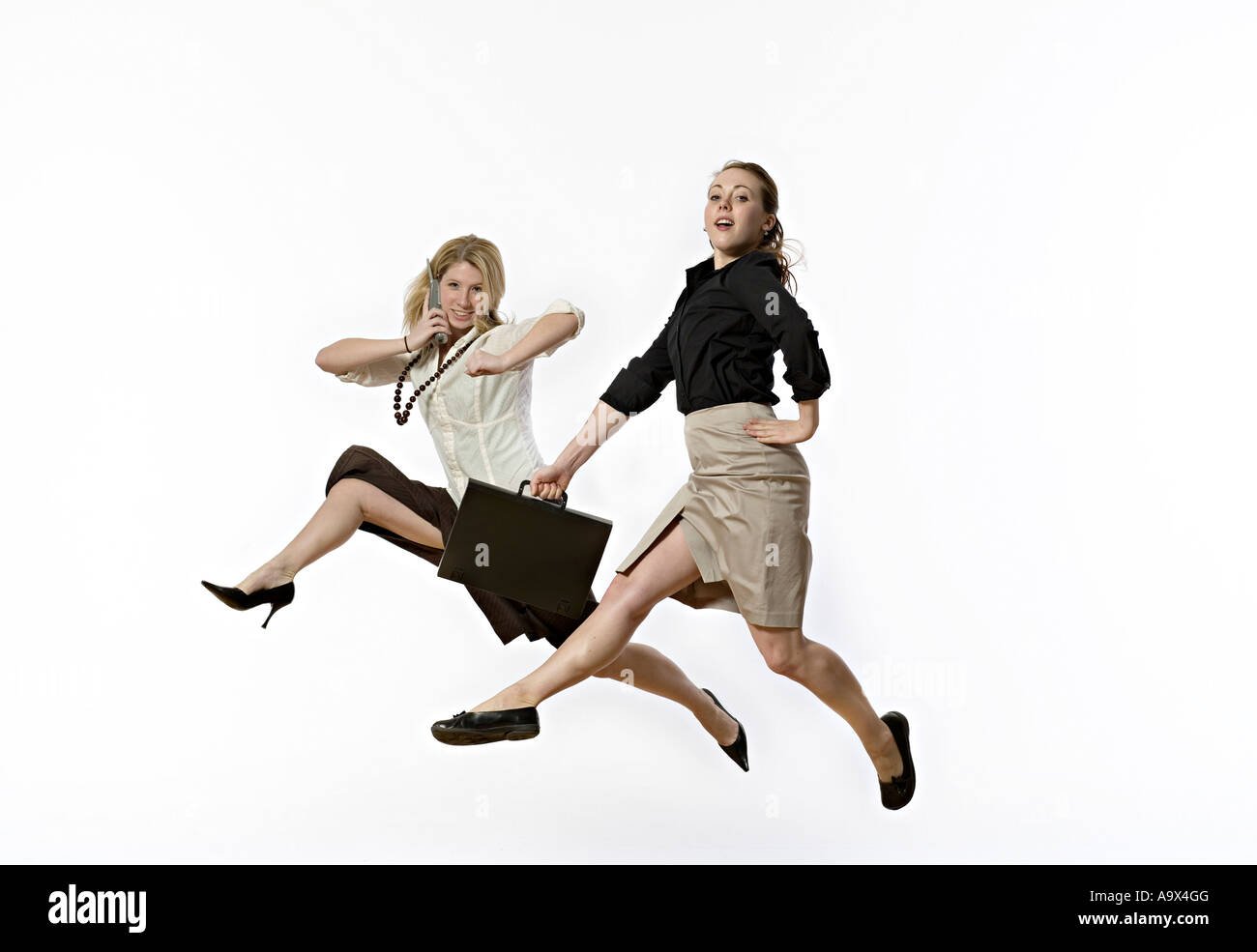 Two women leaping in the air dressed in conservative business attire ...
