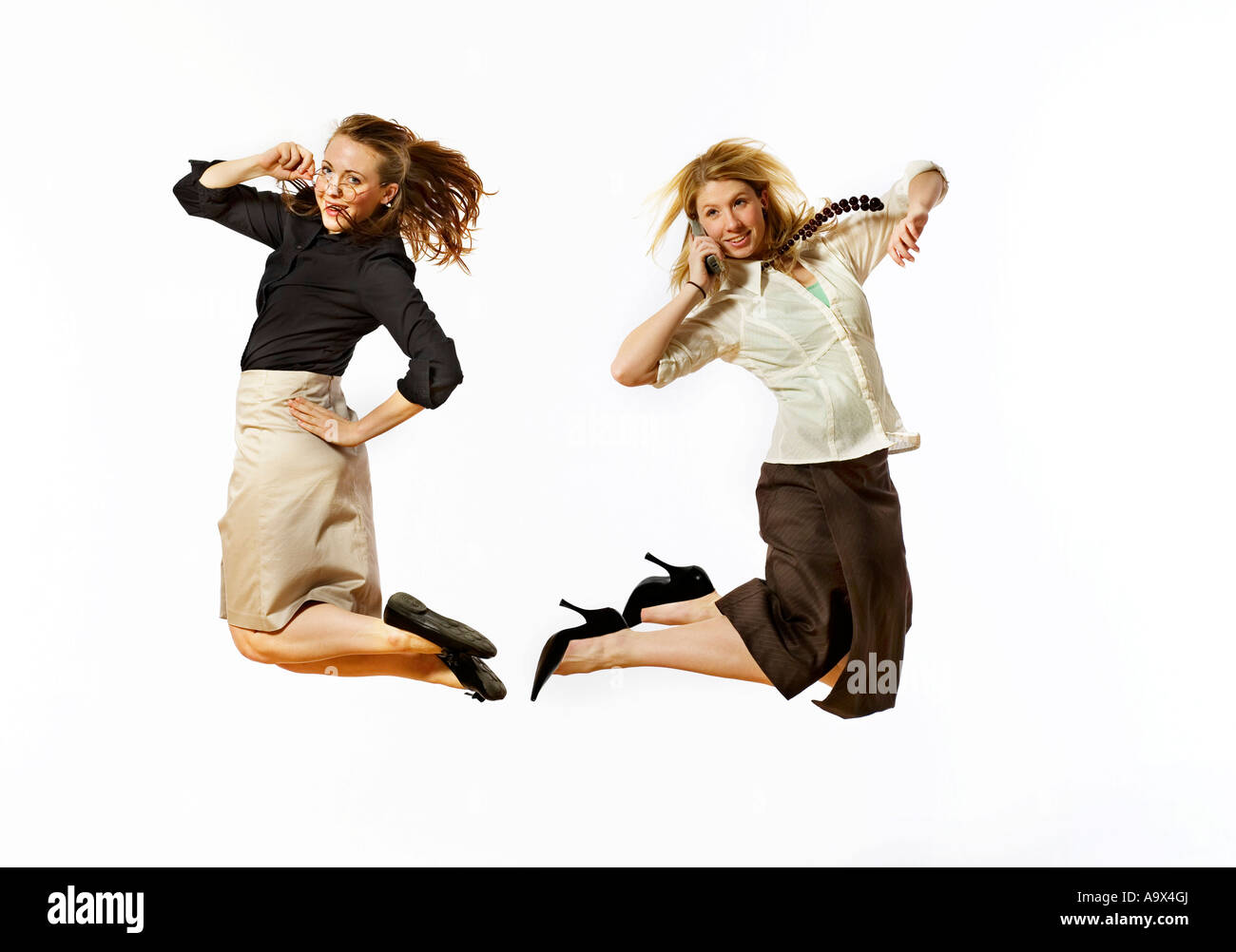 two lovely young women jumping in the air, one holding her glasses, the ...