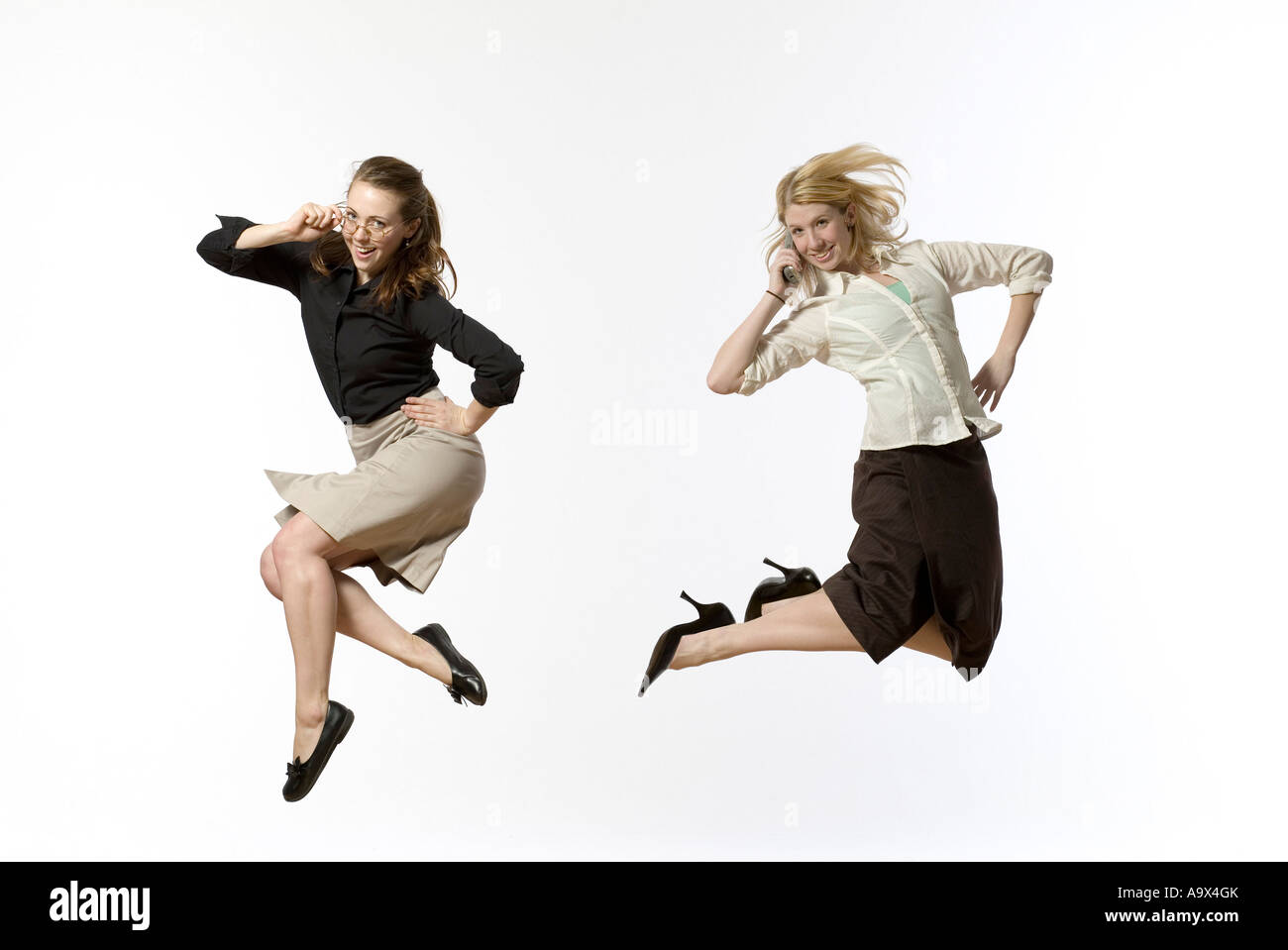 two young business women jumping happily into the air in conservative ...