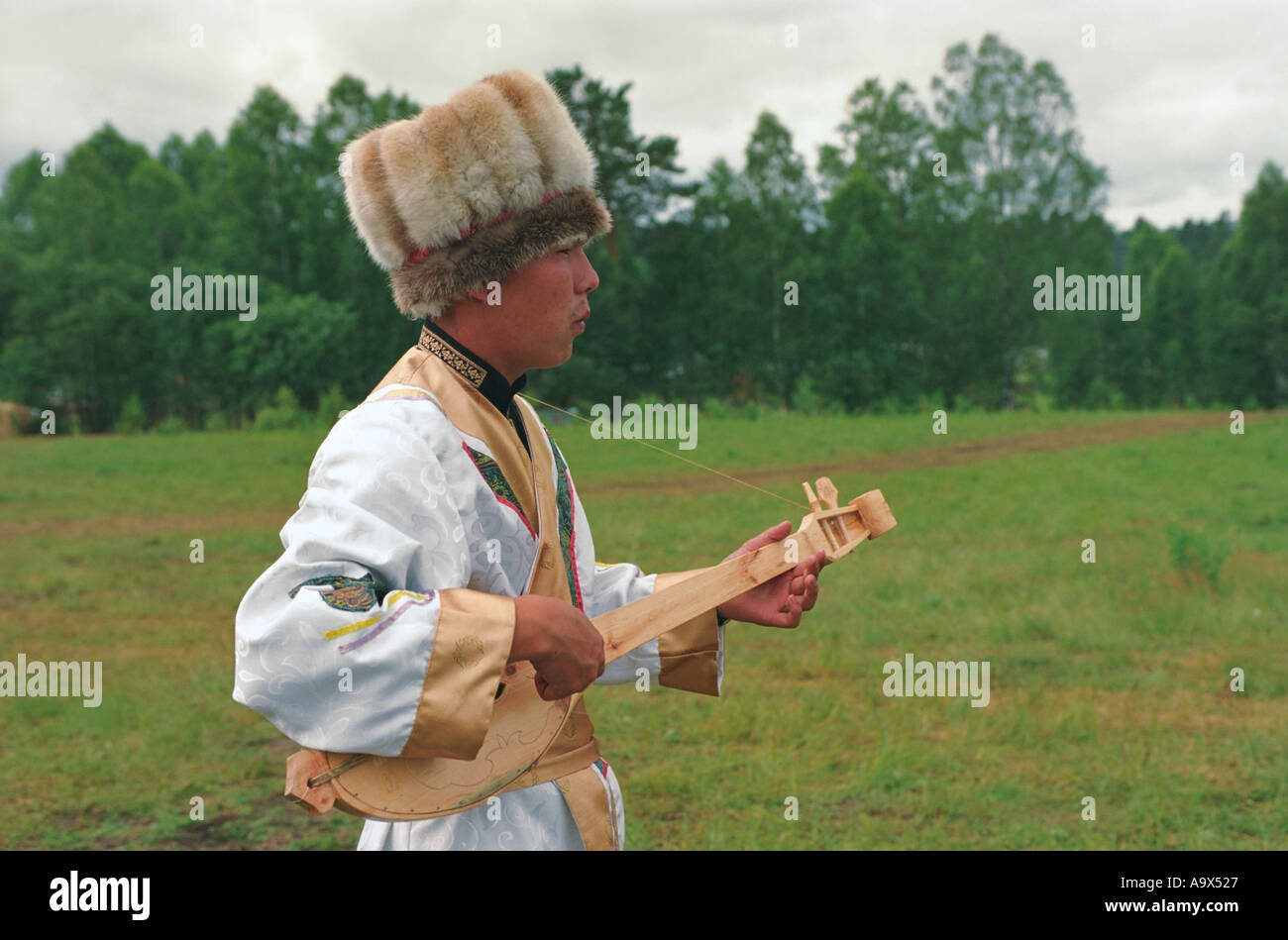 Man in Altaic costume is playing national music instrument topshur and ...