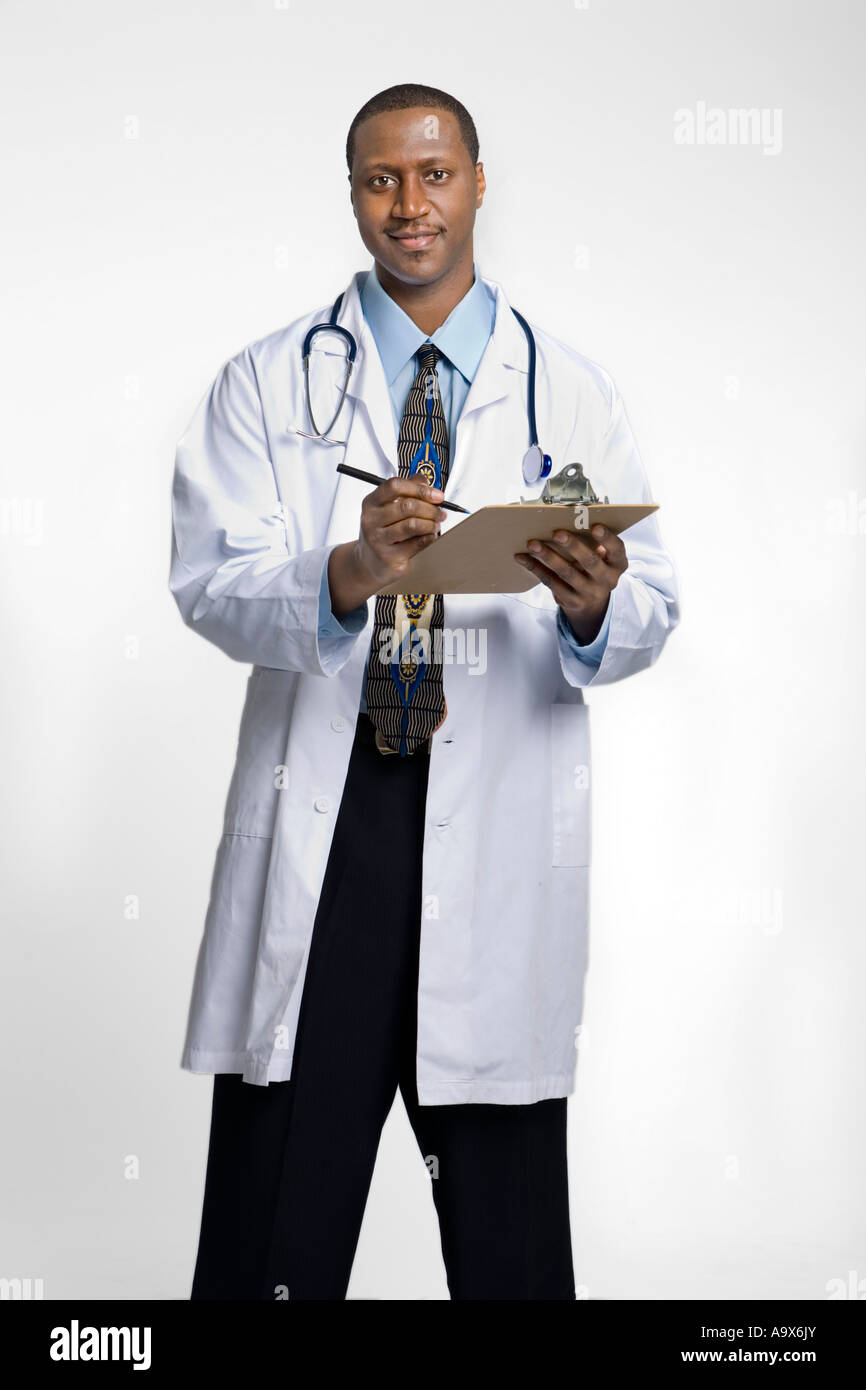 Young black doctor wearing a white coat and stethoscope writing on a ...