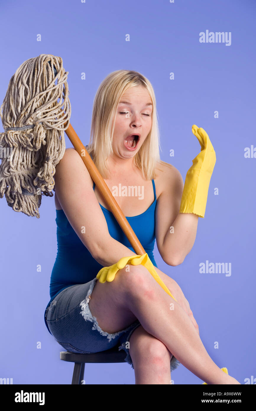 Young woman yawning as though tired after cleaning work wearing rubber ...