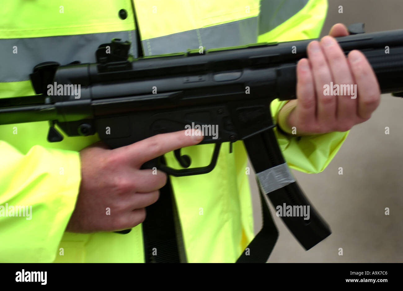 a police officer in a reflective jacket holding a heckler and koch MP5 ...