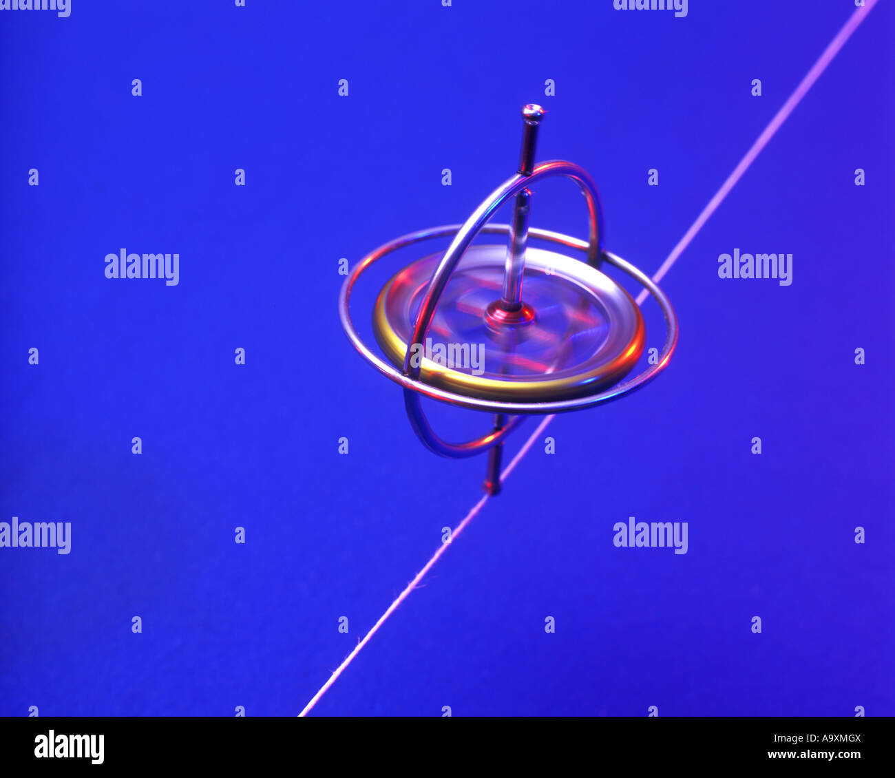 SPINNING GYROSCOPE BALANCES SUSPENDED ON STRING BLUE BACKGROUND Stock ...