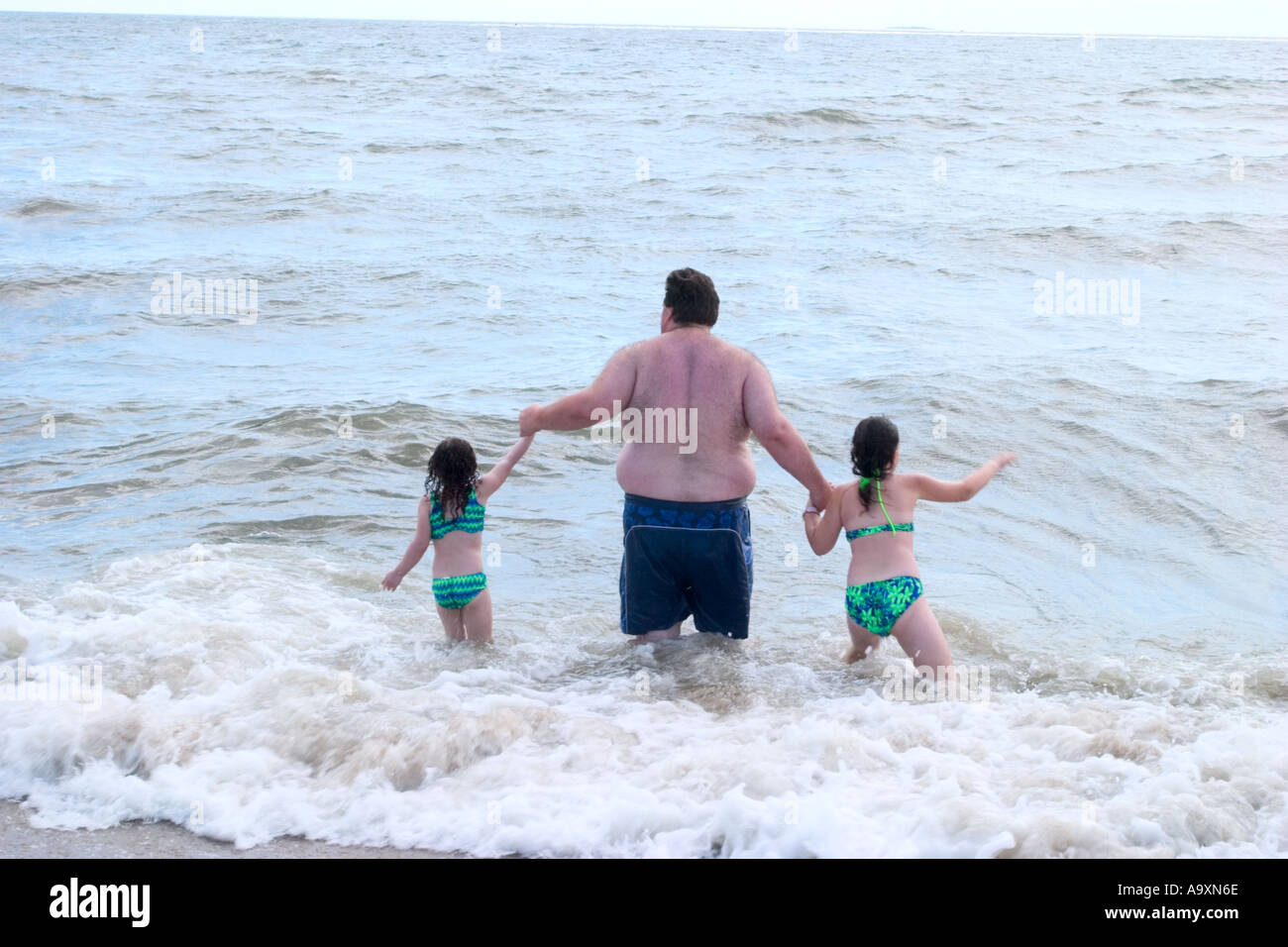 Overweight father and his two daughters playing in the water at the ...