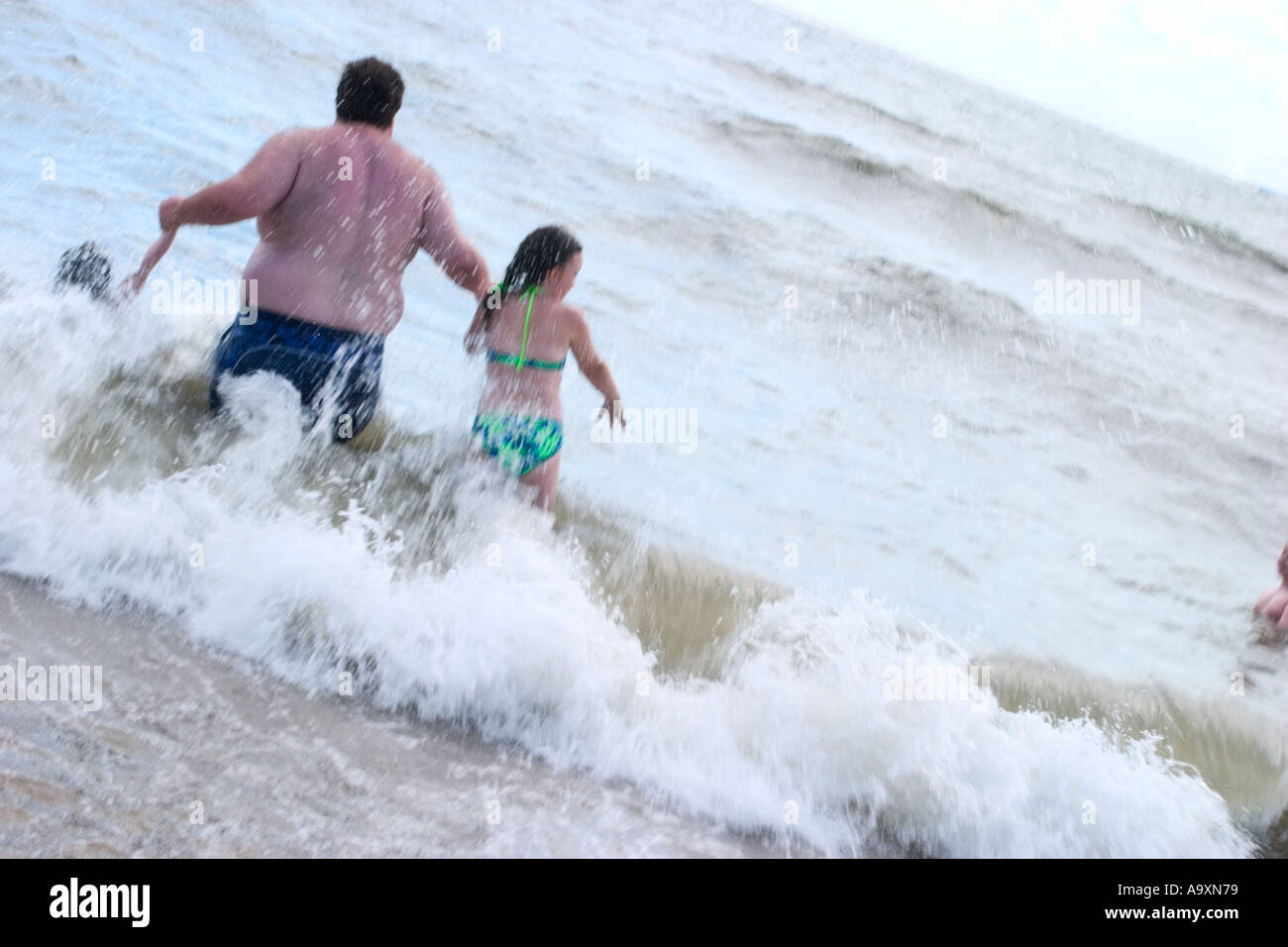 Overweight father and his two daughters playing in the water at the ...