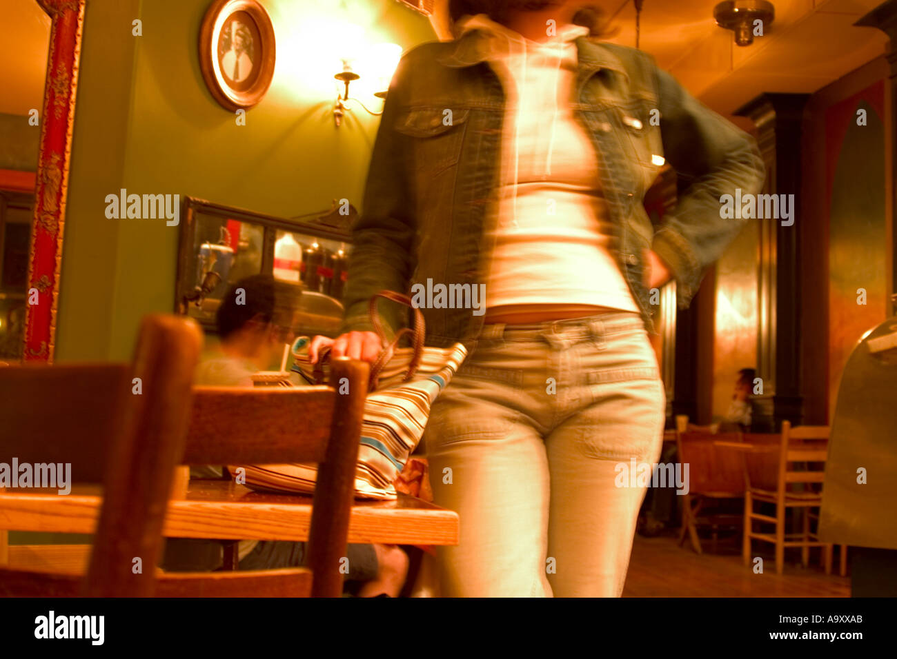 Young woman standing by a chair in a restaurant Stock Photo - Alamy