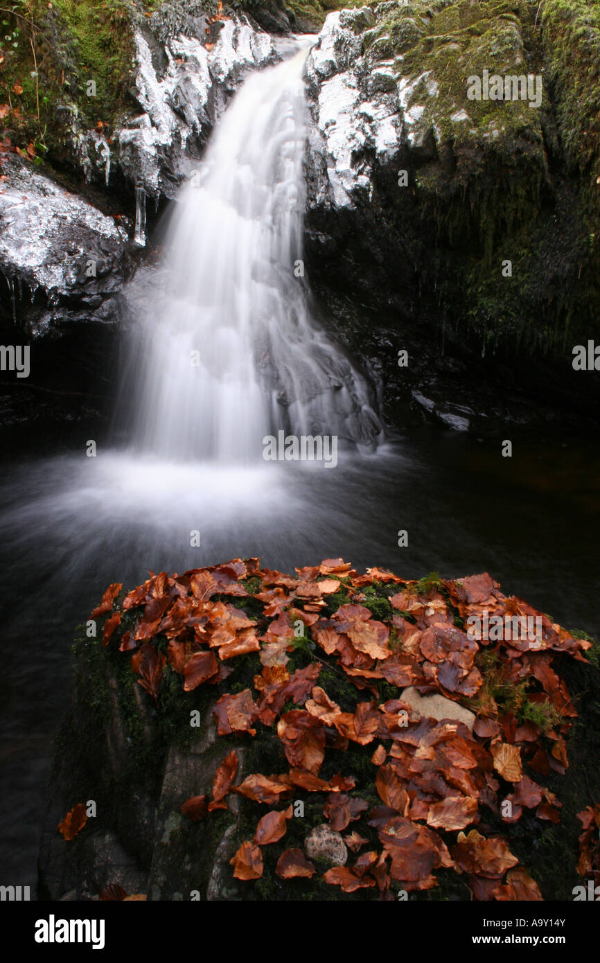 Water cascades down an icy waterfall in winter in the foregroand a ...