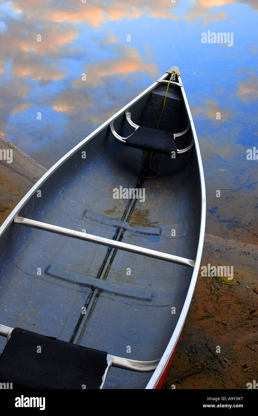 Empty Canoe On Shore with Cloud Reflections on Water Stock Photo - Alamy