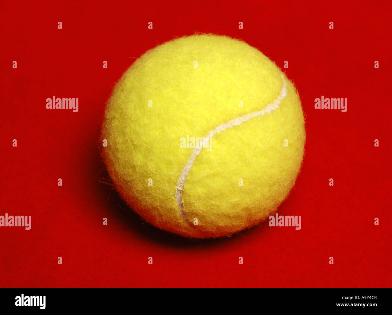 Yellow tennis ball on red background Stock Photo - Alamy