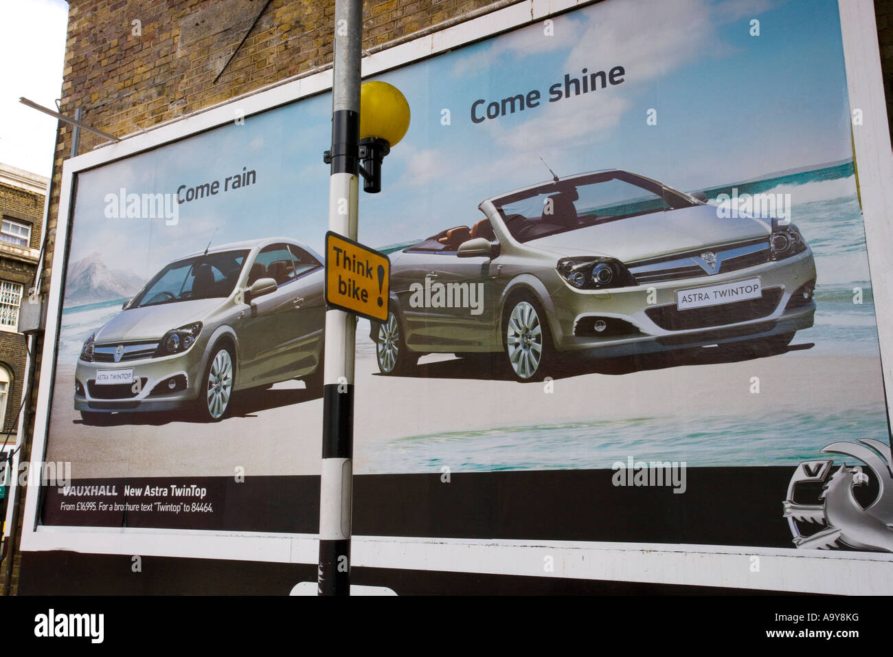 juxtaposition of car poster with bike sign shows humour Stock Photo - Alamy
