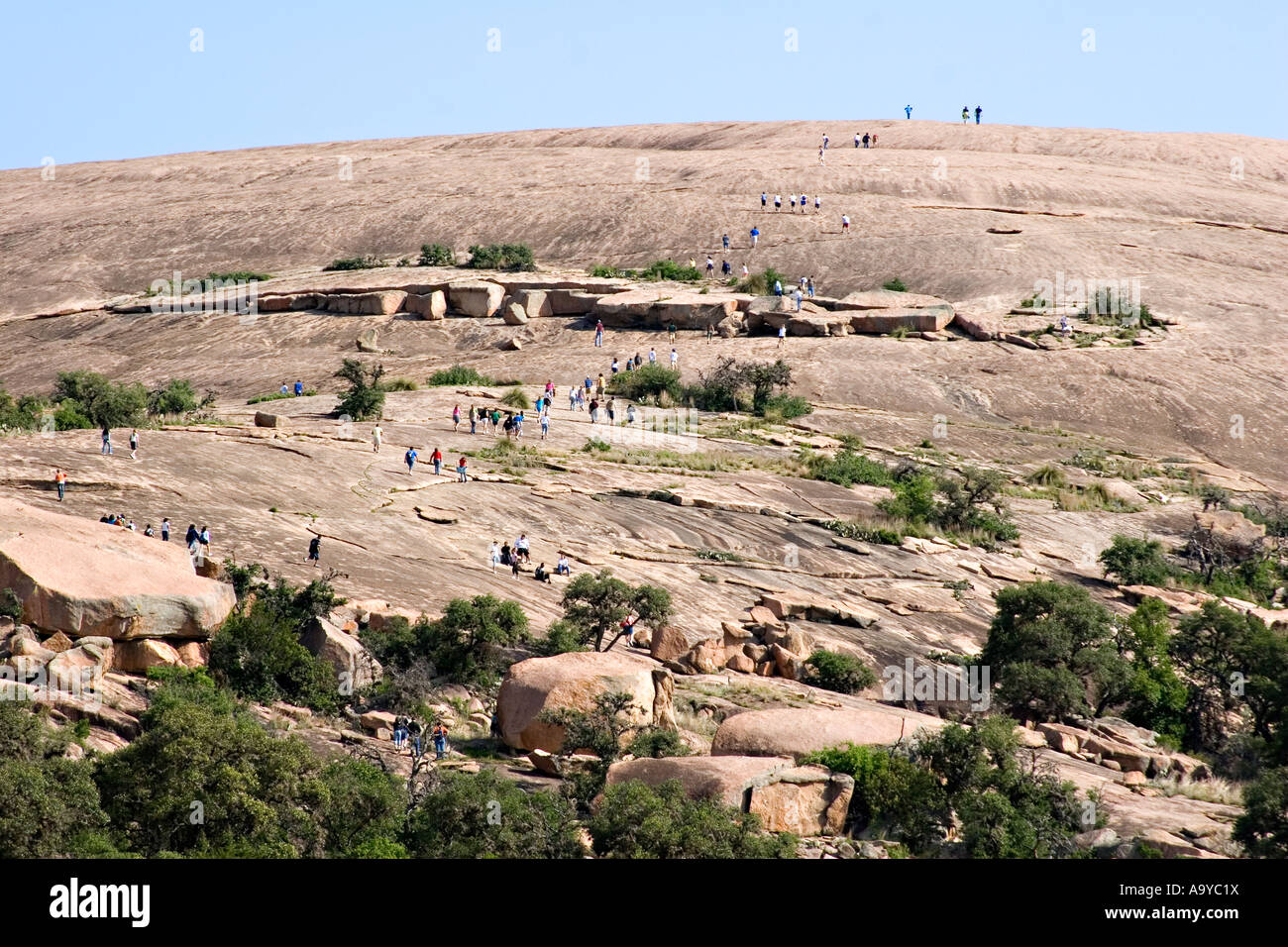 Tourists climbing the Enchanted Rock main dome at Enchanted Rock State ...