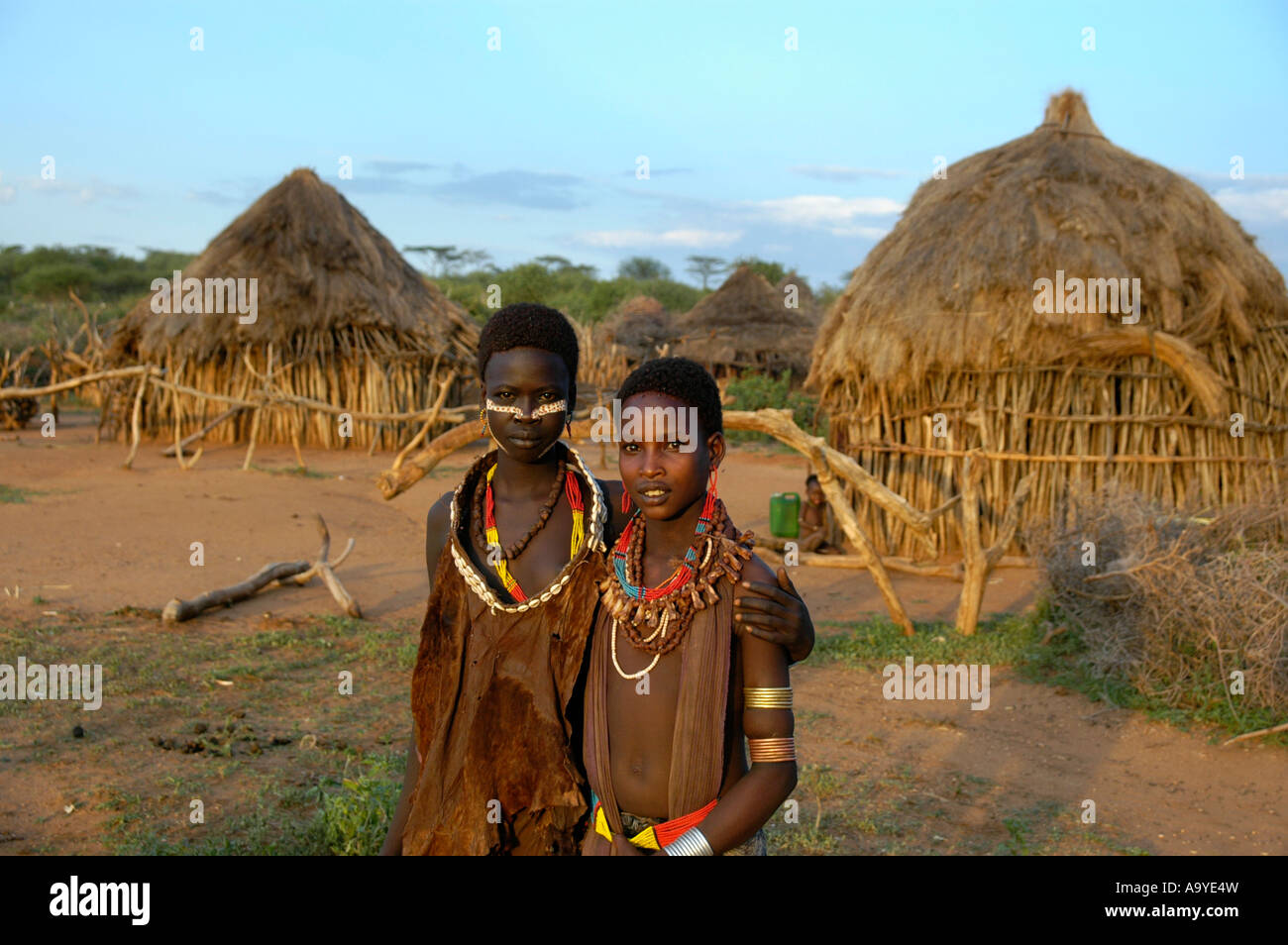 Two colourful decorated girls of the Hamar people in front of a straw ...