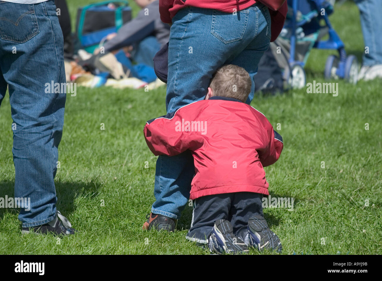 Young boy playfully holding onto the legs of an adult Stock Photo - Alamy