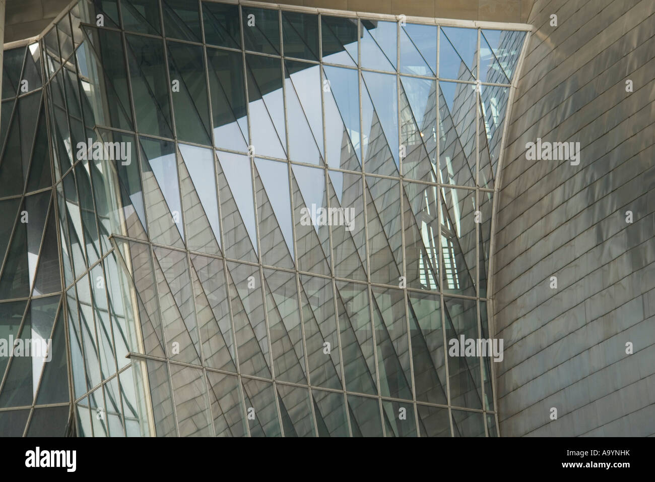 undulating titanium clad walls reflected in the glass atrium of the ...