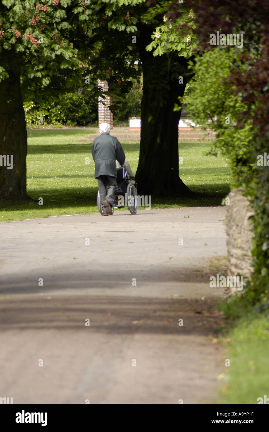 old man pushing old woman in wheelchair through the park Stock Photo ...