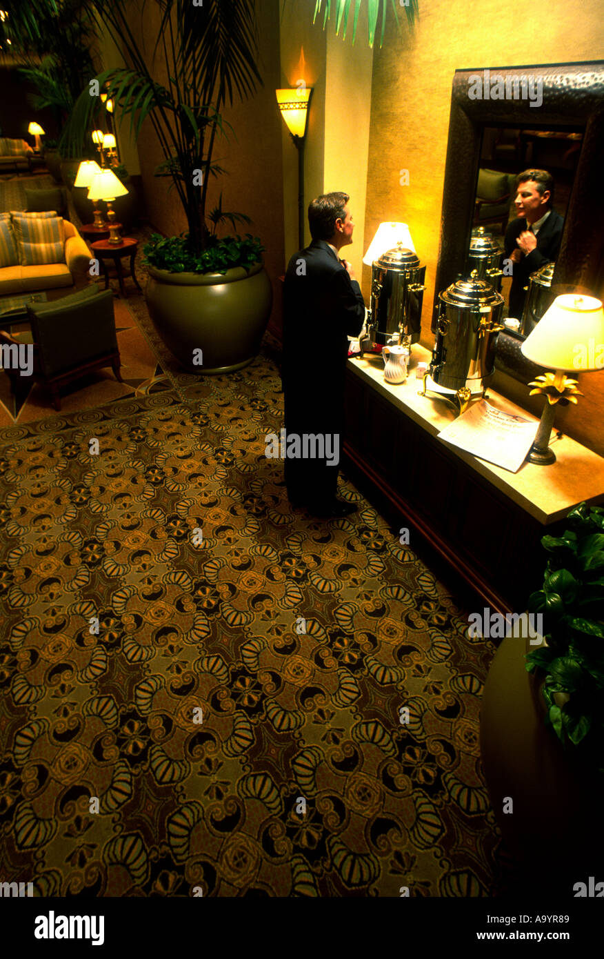 An executive straightens his tie in the hotel mirror before going into ...