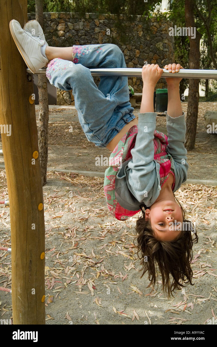 young girl hanging upside down on climbing bar in playground Stock Photo - Alamy