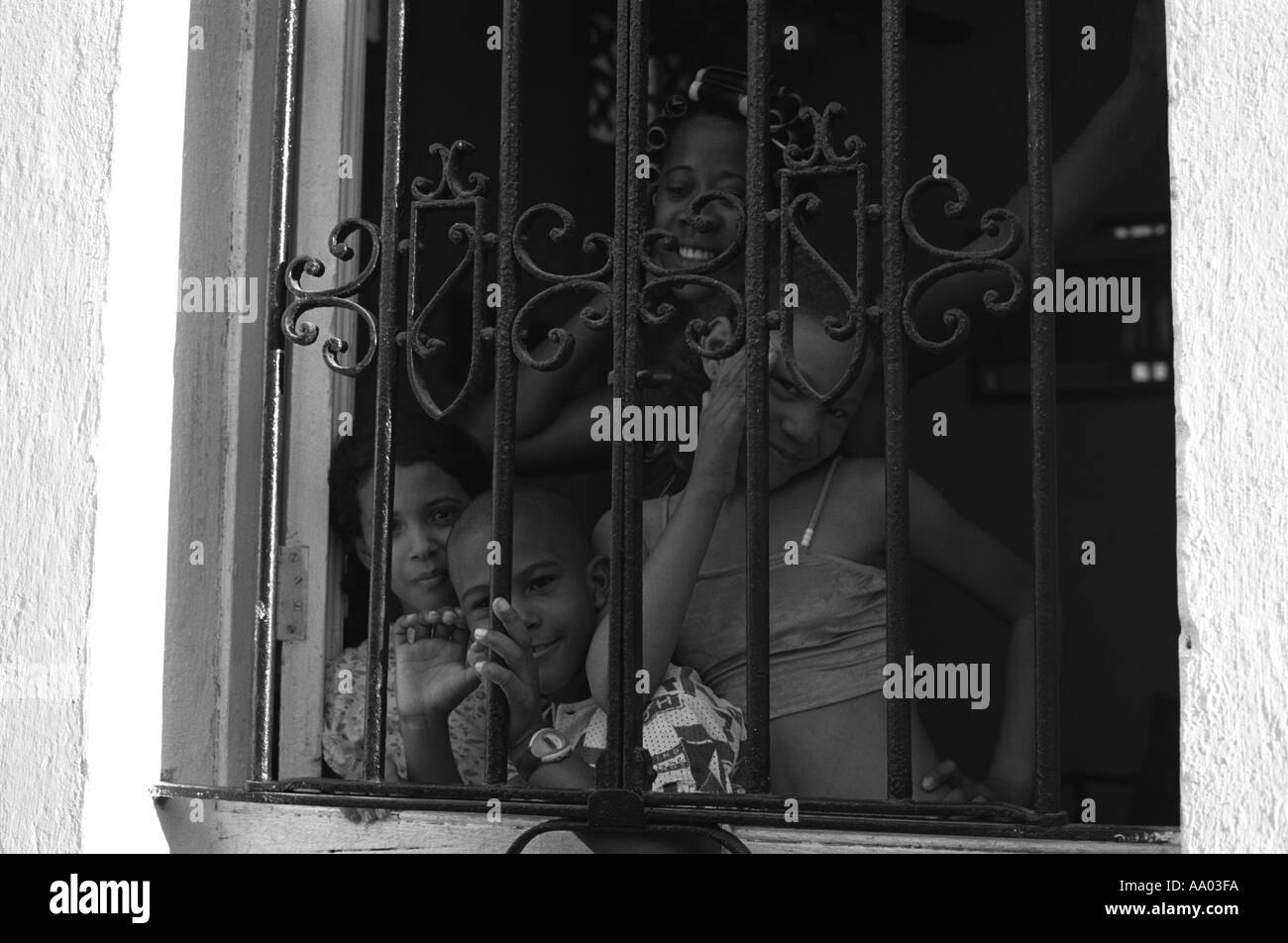 Urban family in Havana Cuba playfully standing behind barricaded window ...