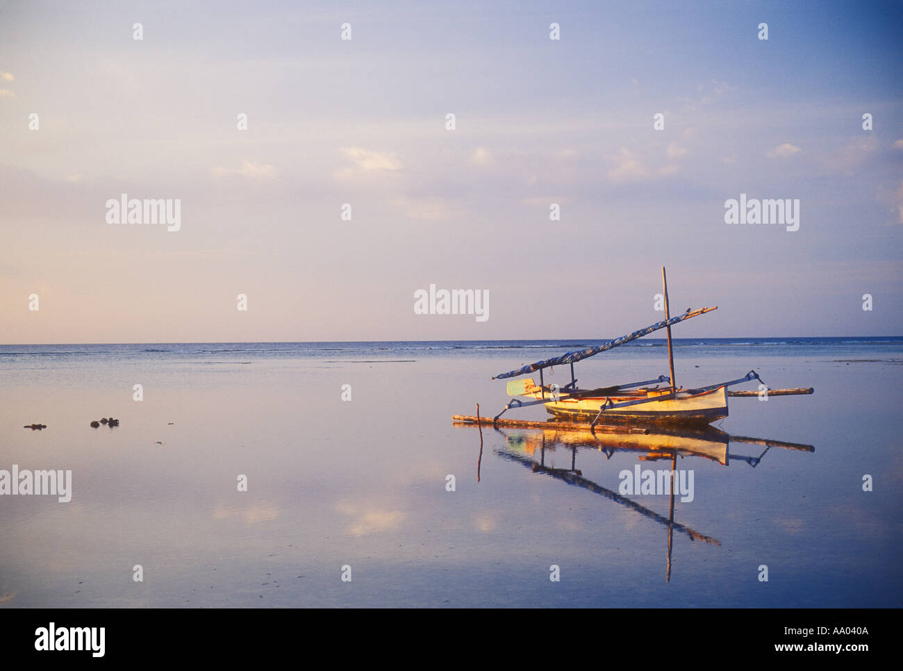 Traditional outrigger canoe sitting at rest in calm water Lombok Island ...