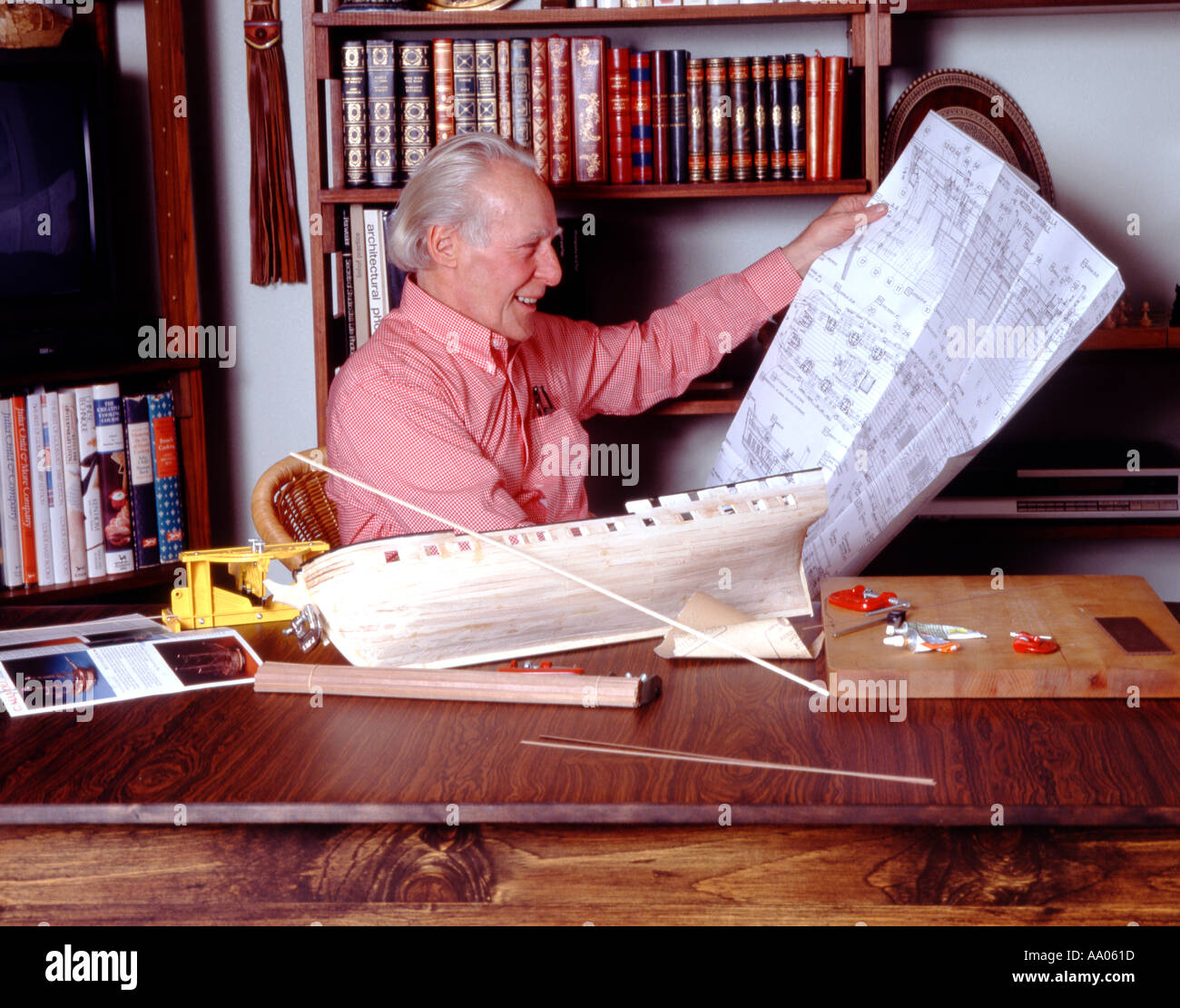 Senior Citizen model maker checking over plans for a model ship he is ...