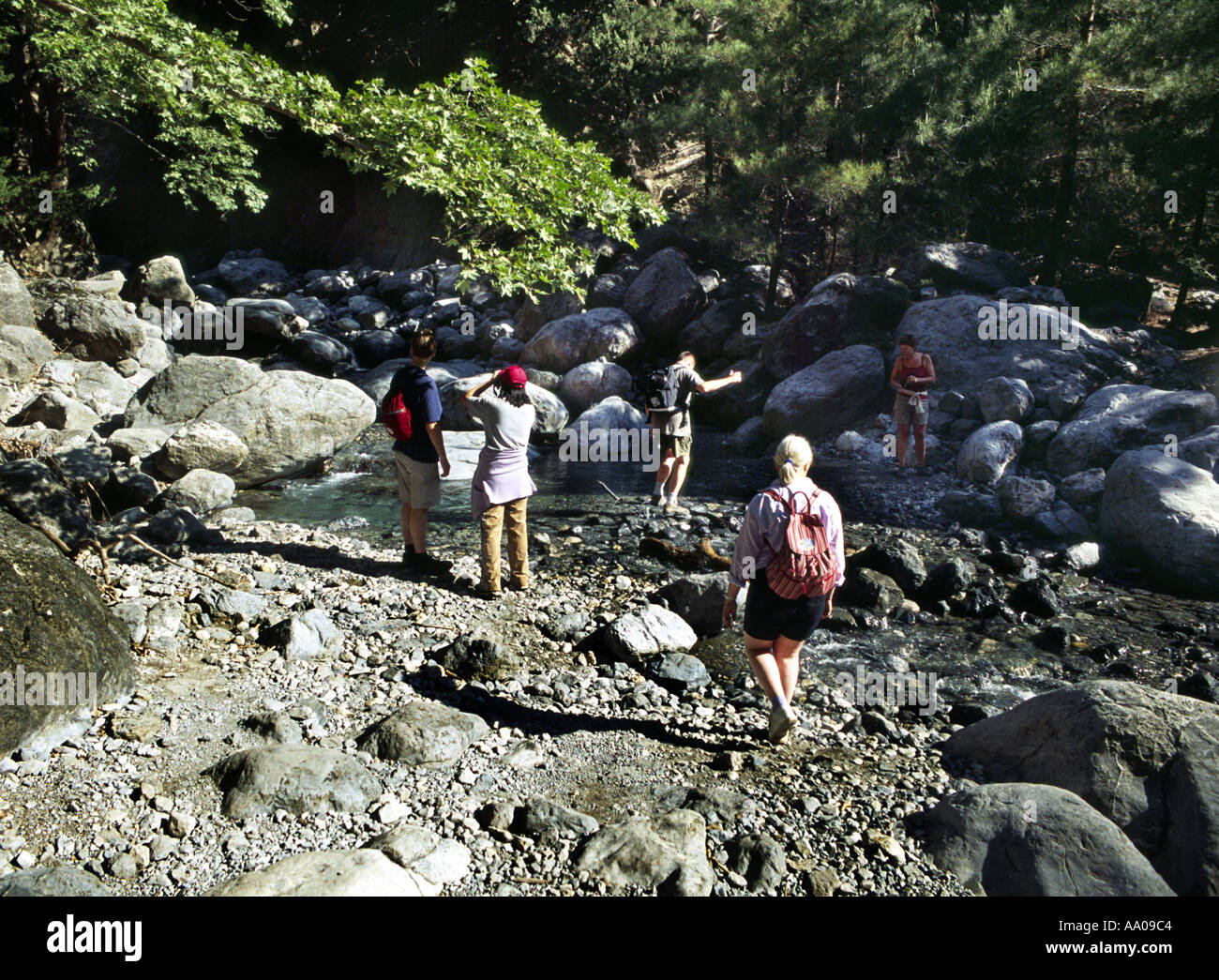 Walkers taking a break in the sunshine at a boulder strewn river ...