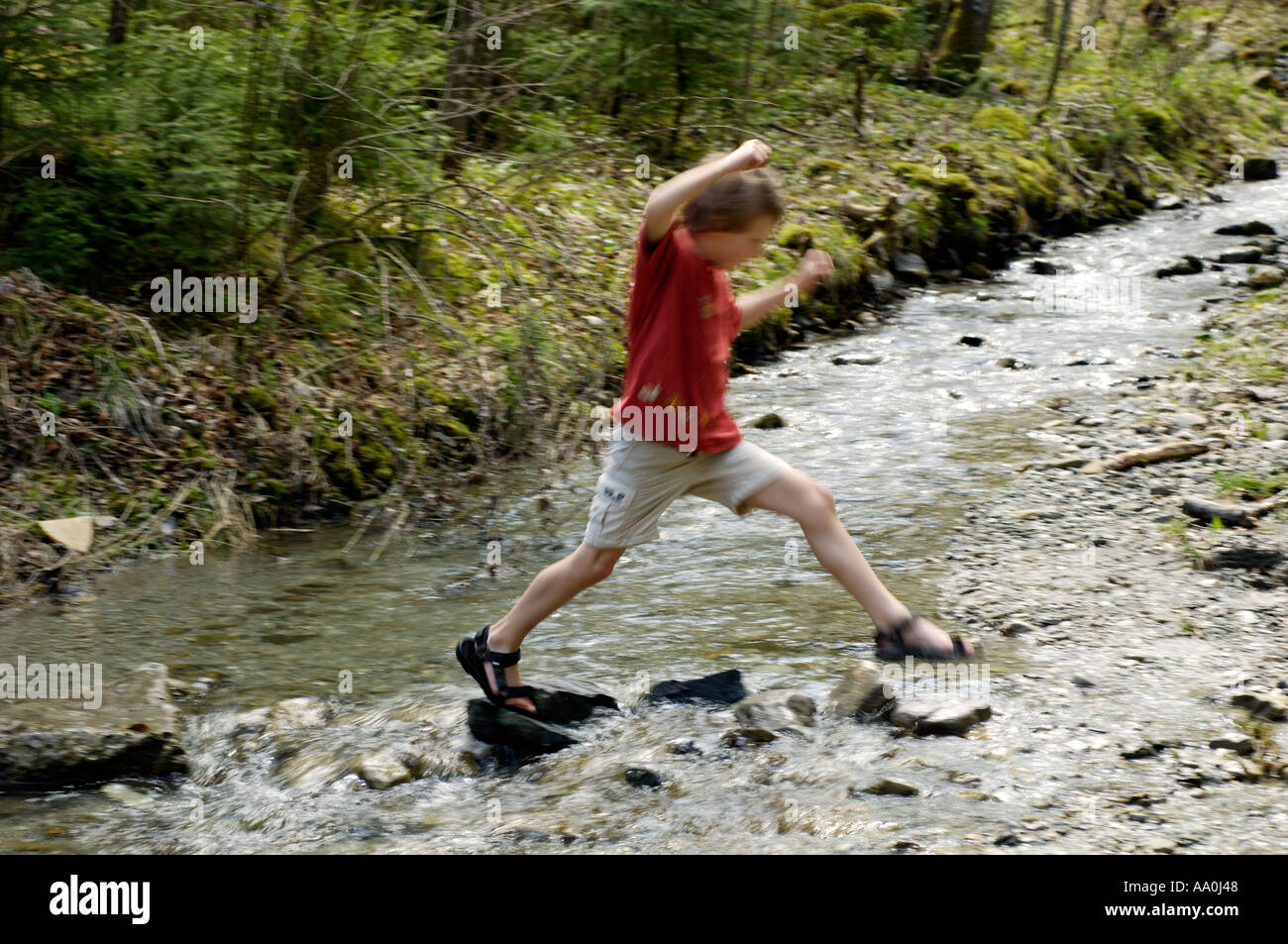 One seven year old boy jumping over brook Stock Photo - Alamy