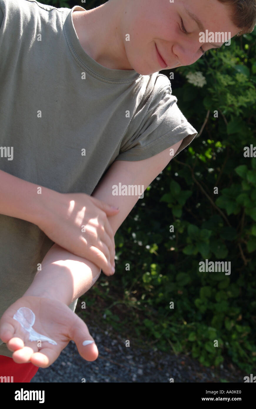 Young boy applying sunscreen to his arm Stock Photo - Alamy
